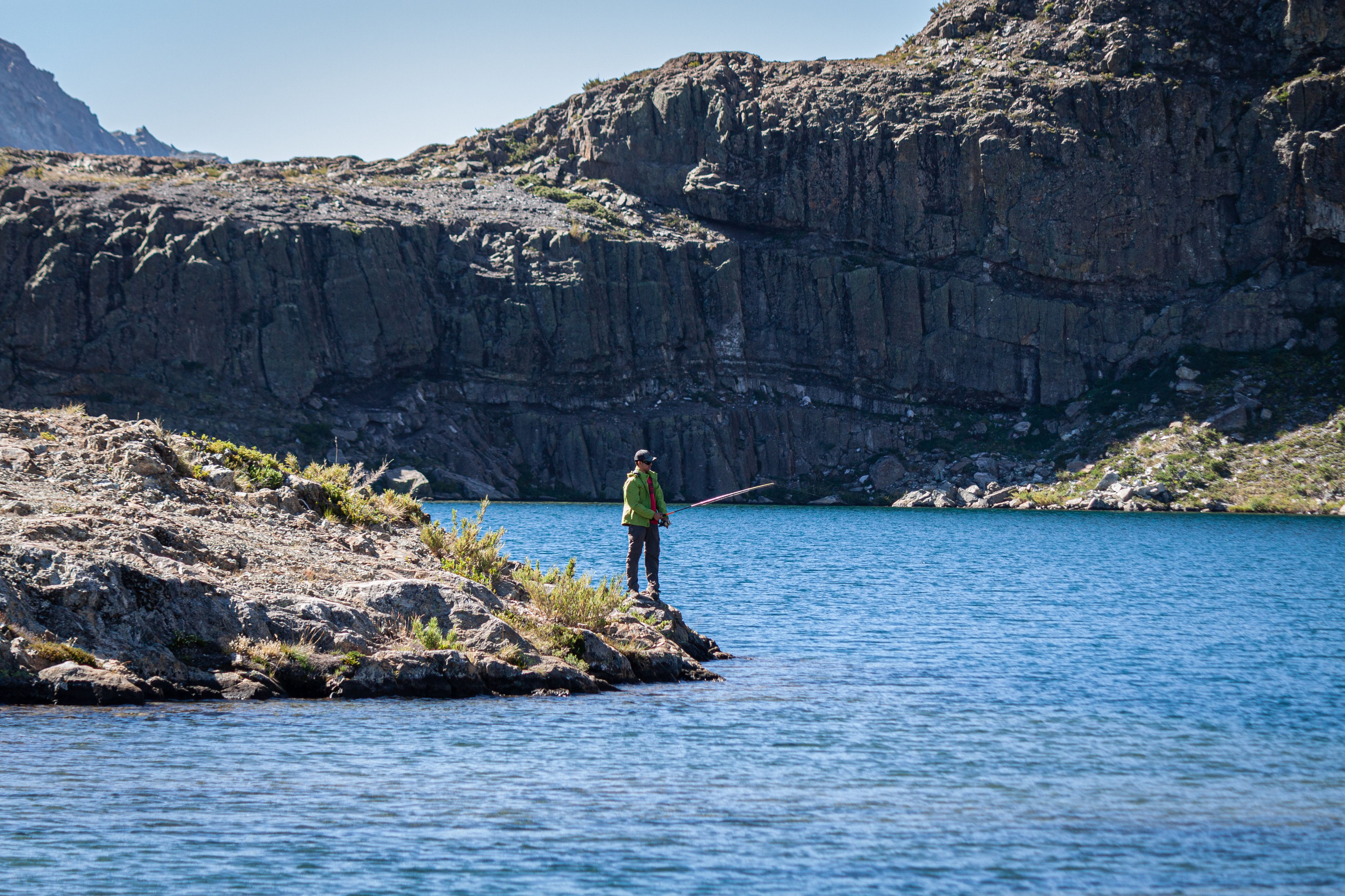 Man Fishing on River Bank in Mountains · Free Stock Photo