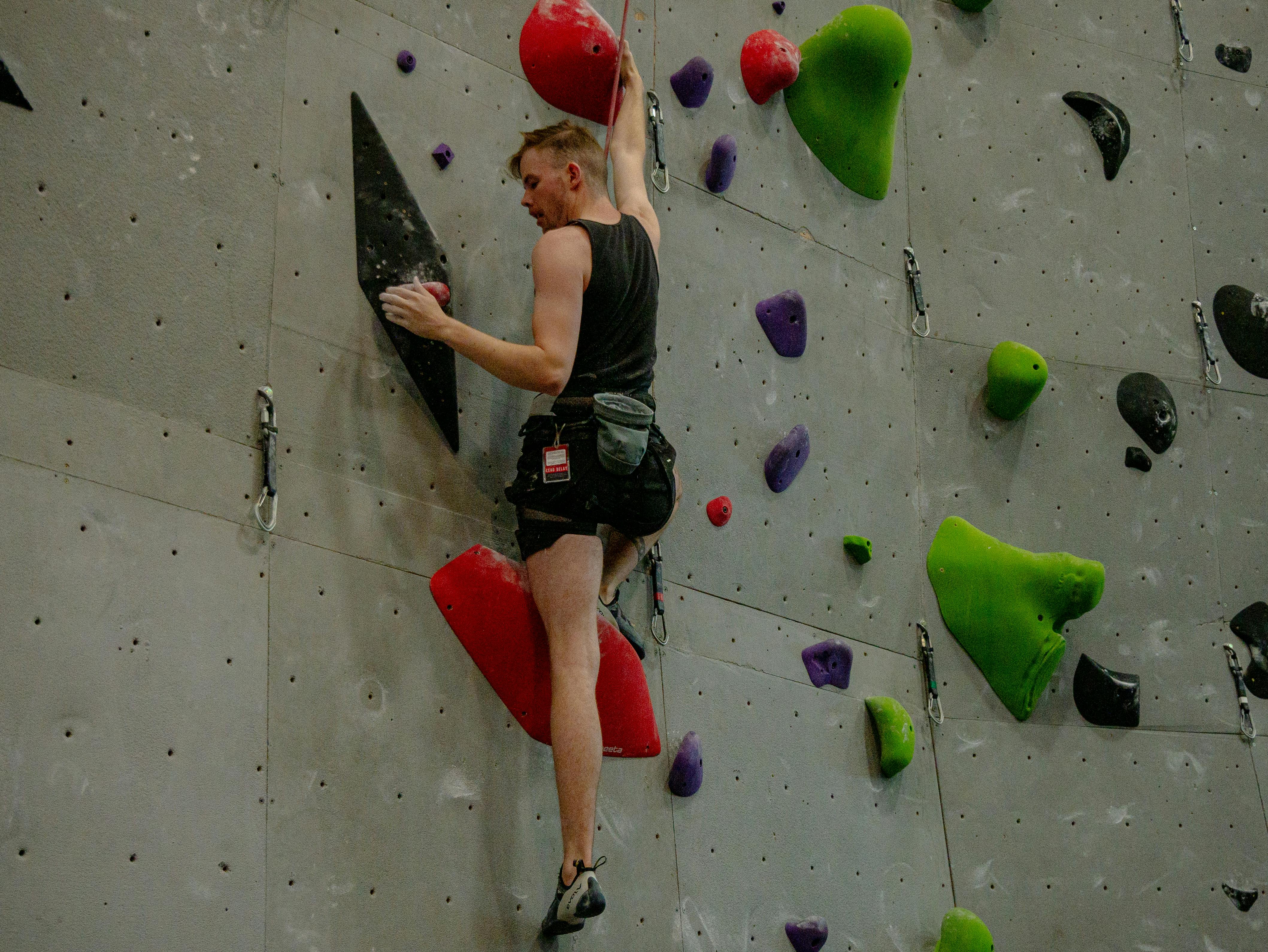 A man climbing on a climbing wall with colorful balls · Free Stock Photo