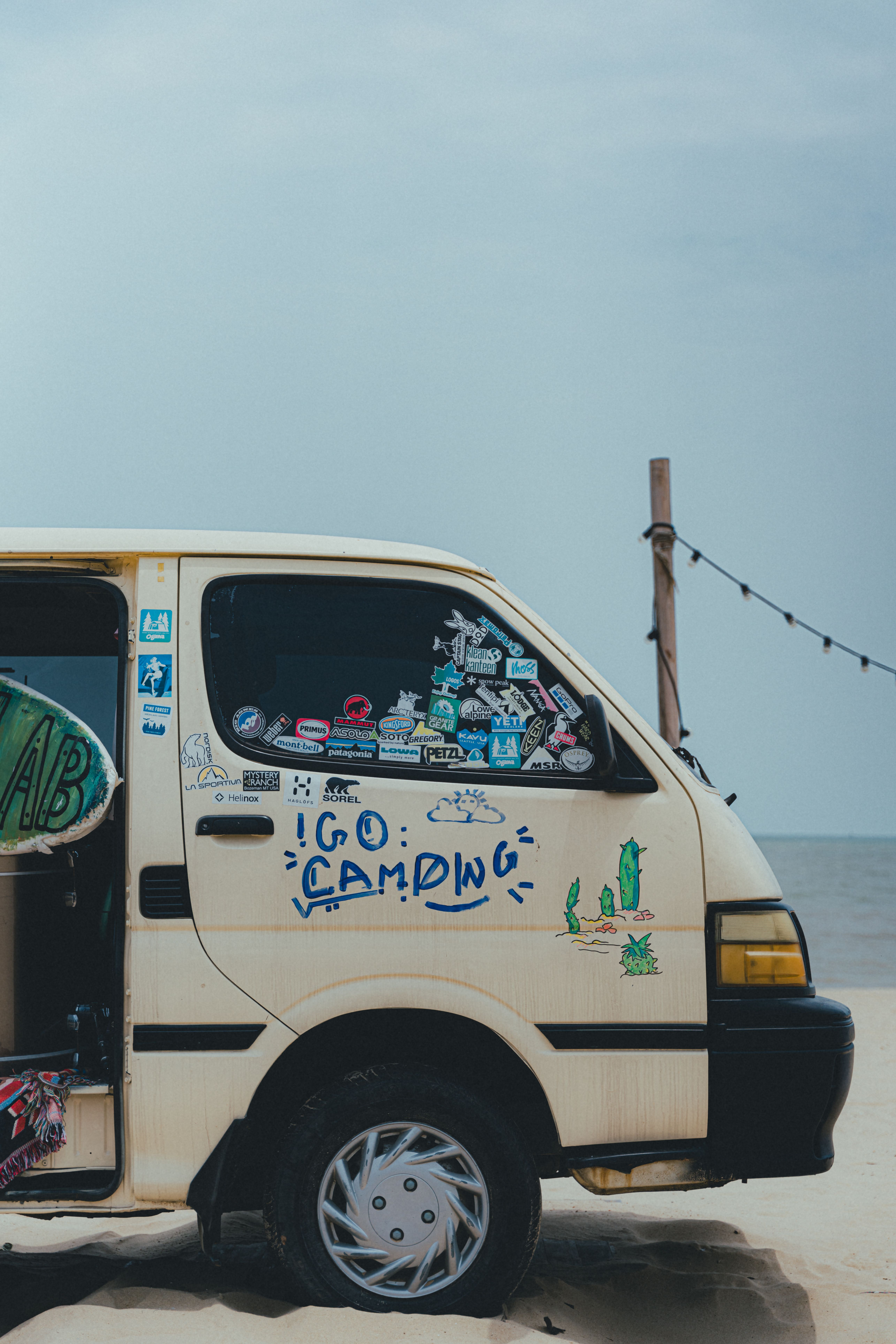 A Vintage Van with Stickers Parked on a Beach · Free Stock Photo