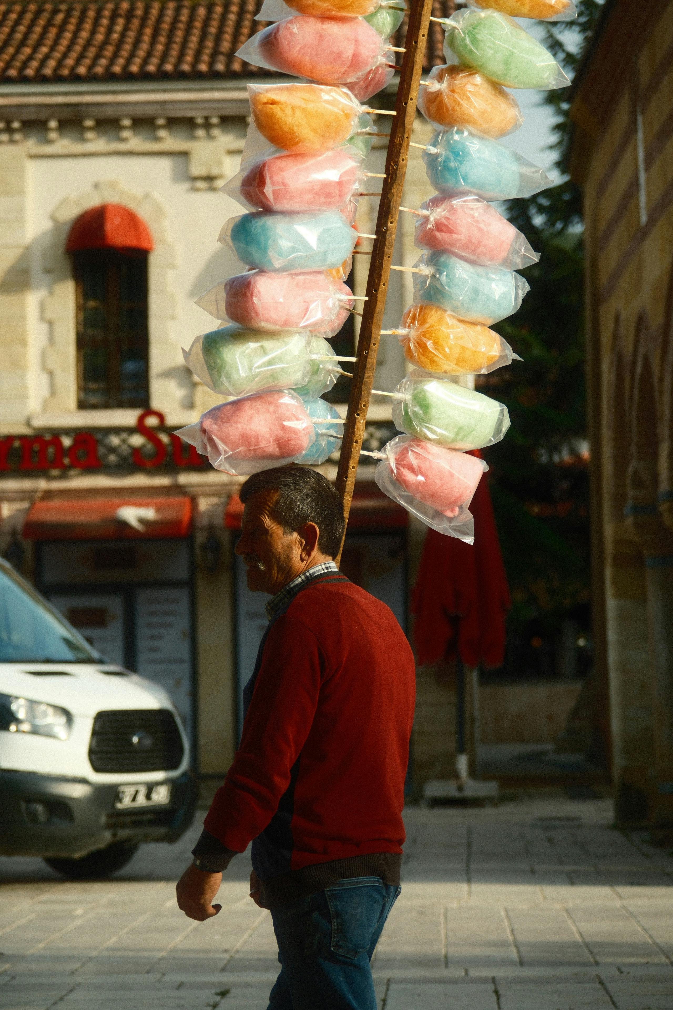 A Man Holding a Stick with Cotton Candy · Free Stock Photo
