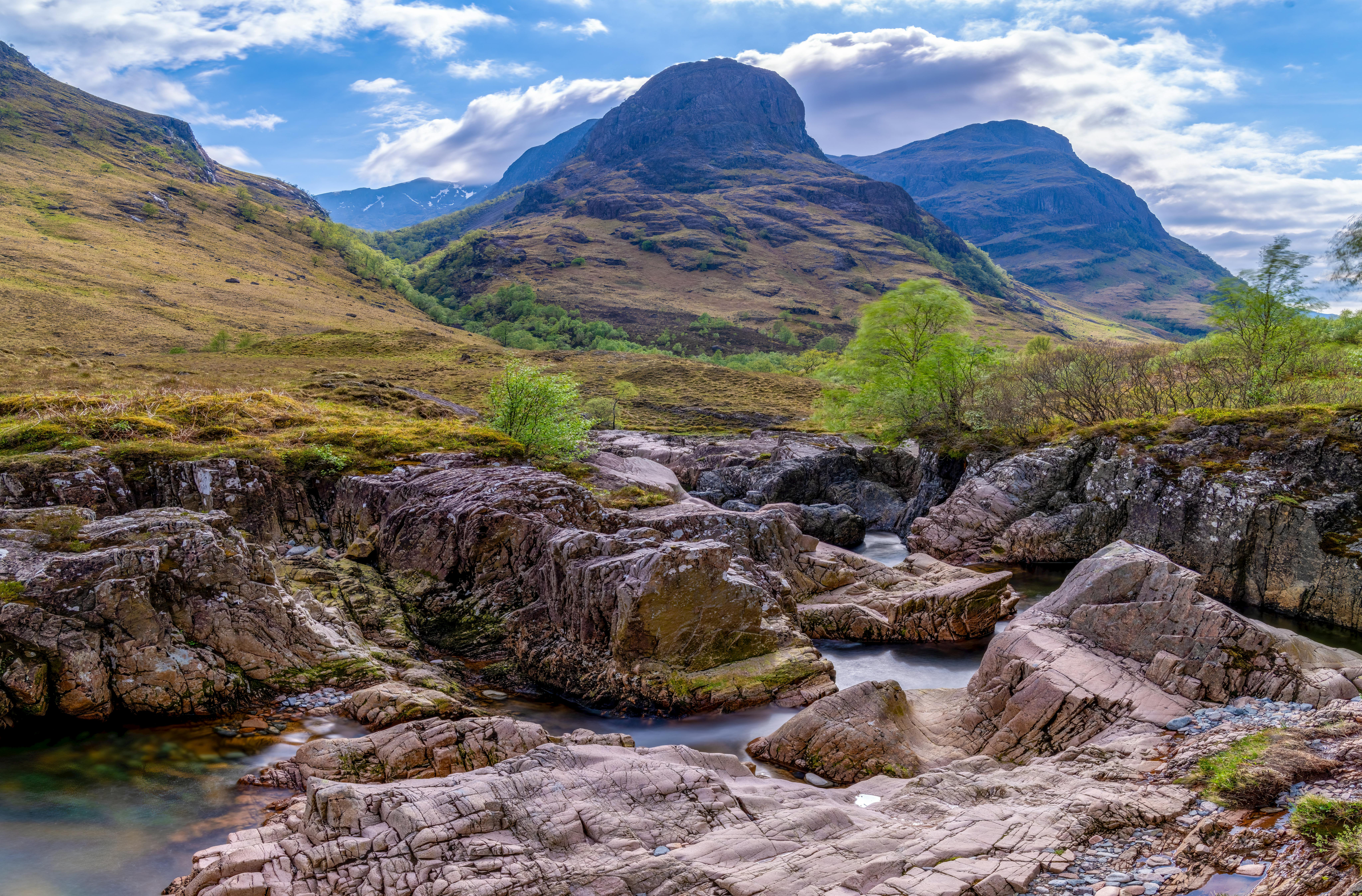 A river flows through a rocky valley with mountains in the background ...