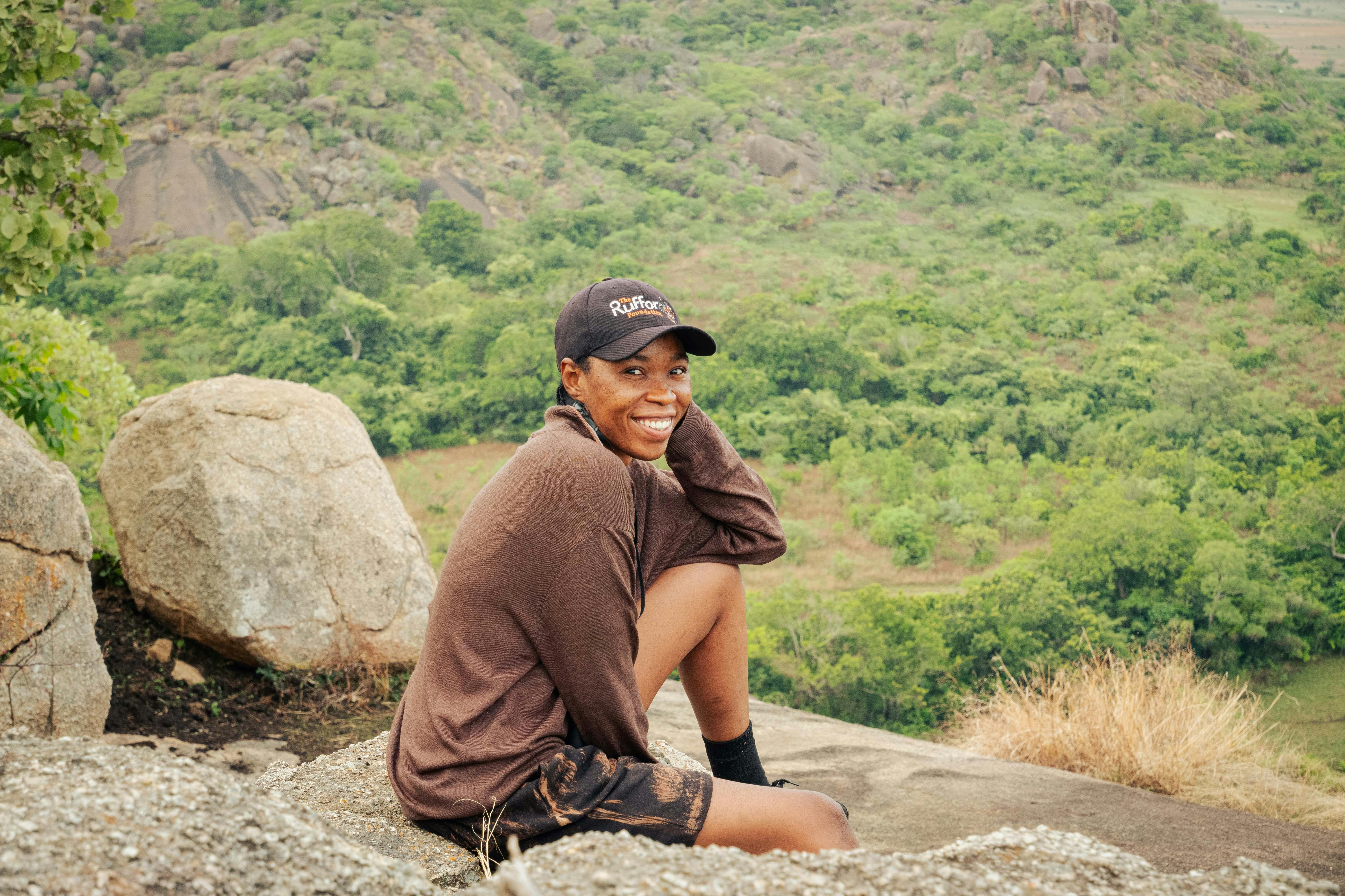 A Woman Sitting on a Rock in Mountains and Smiling · Free Stock Photo
