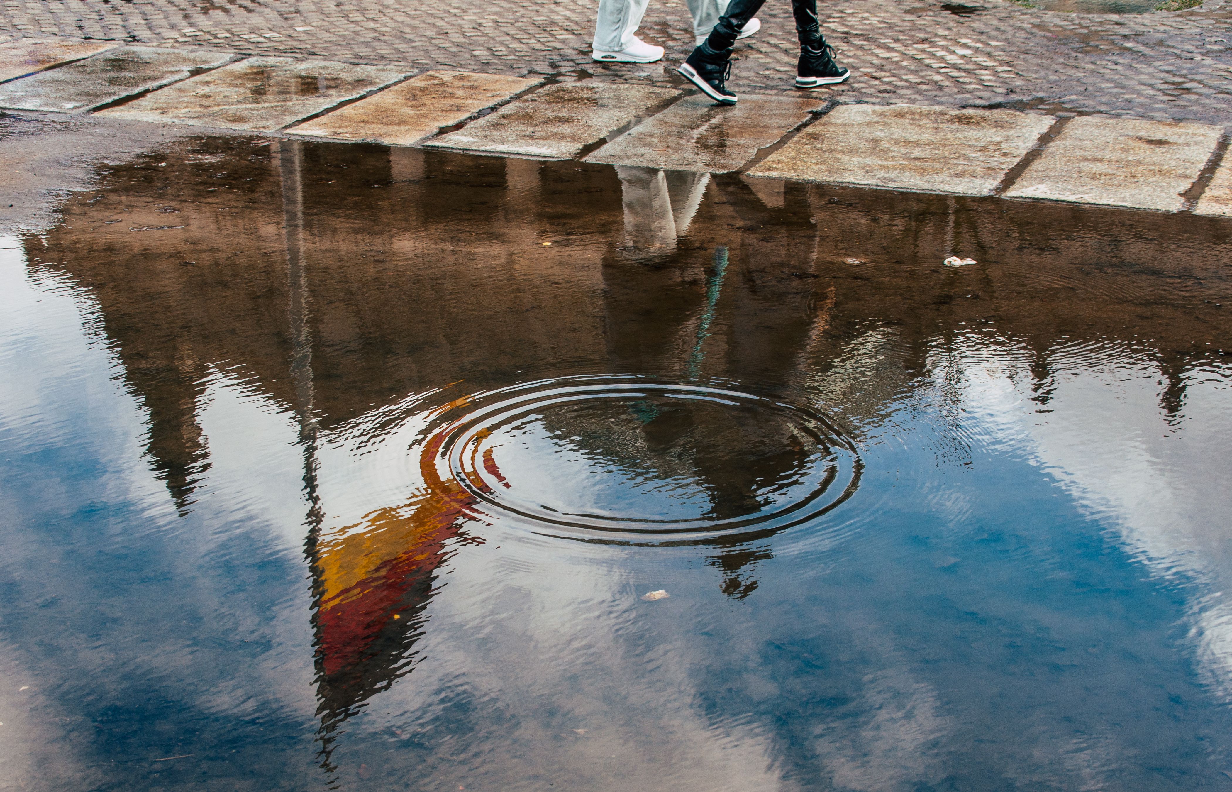 A person walking on a sidewalk with a reflection of a puddle · Free ...