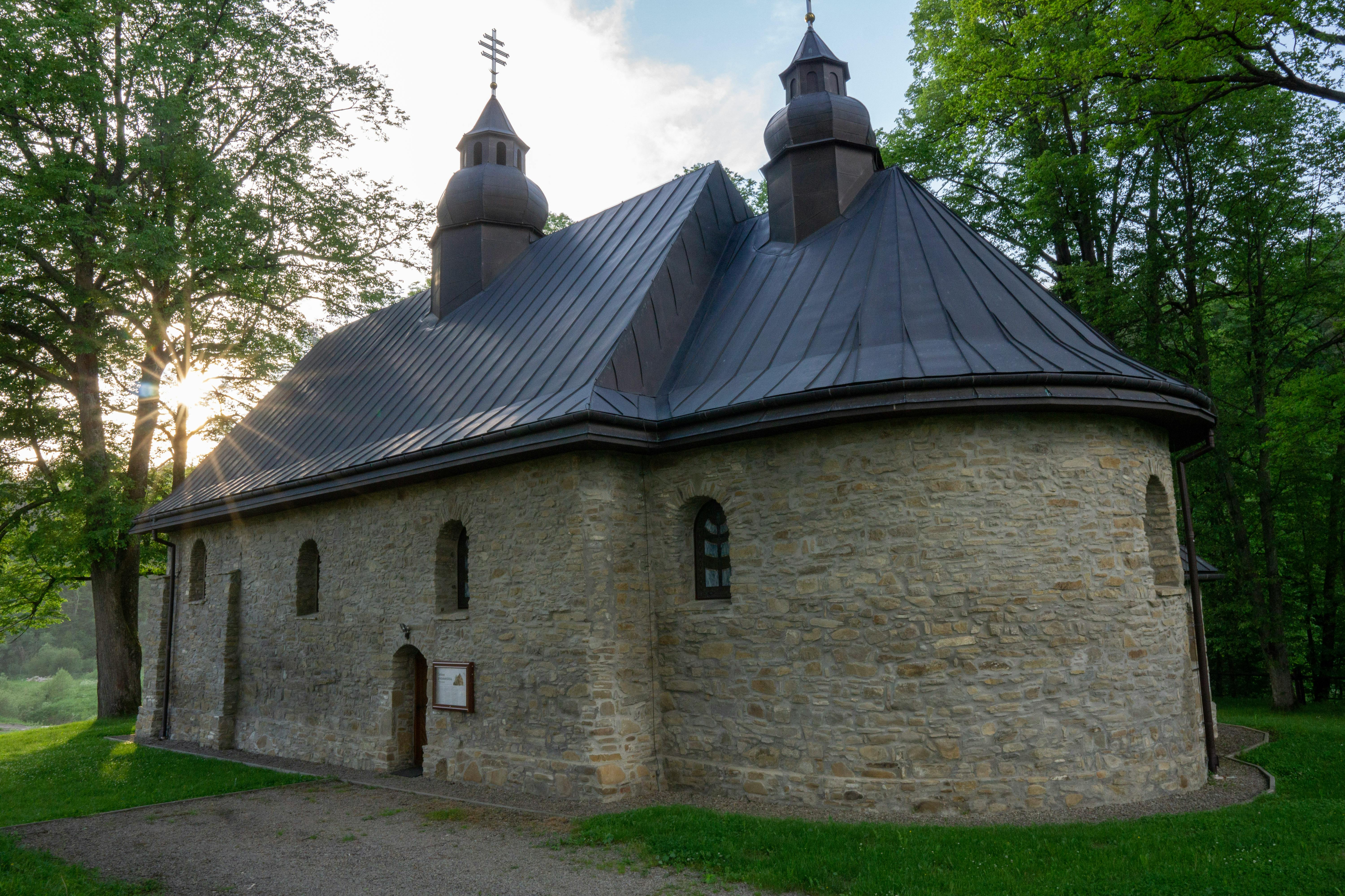 A small stone church with a black roof · Free Stock Photo