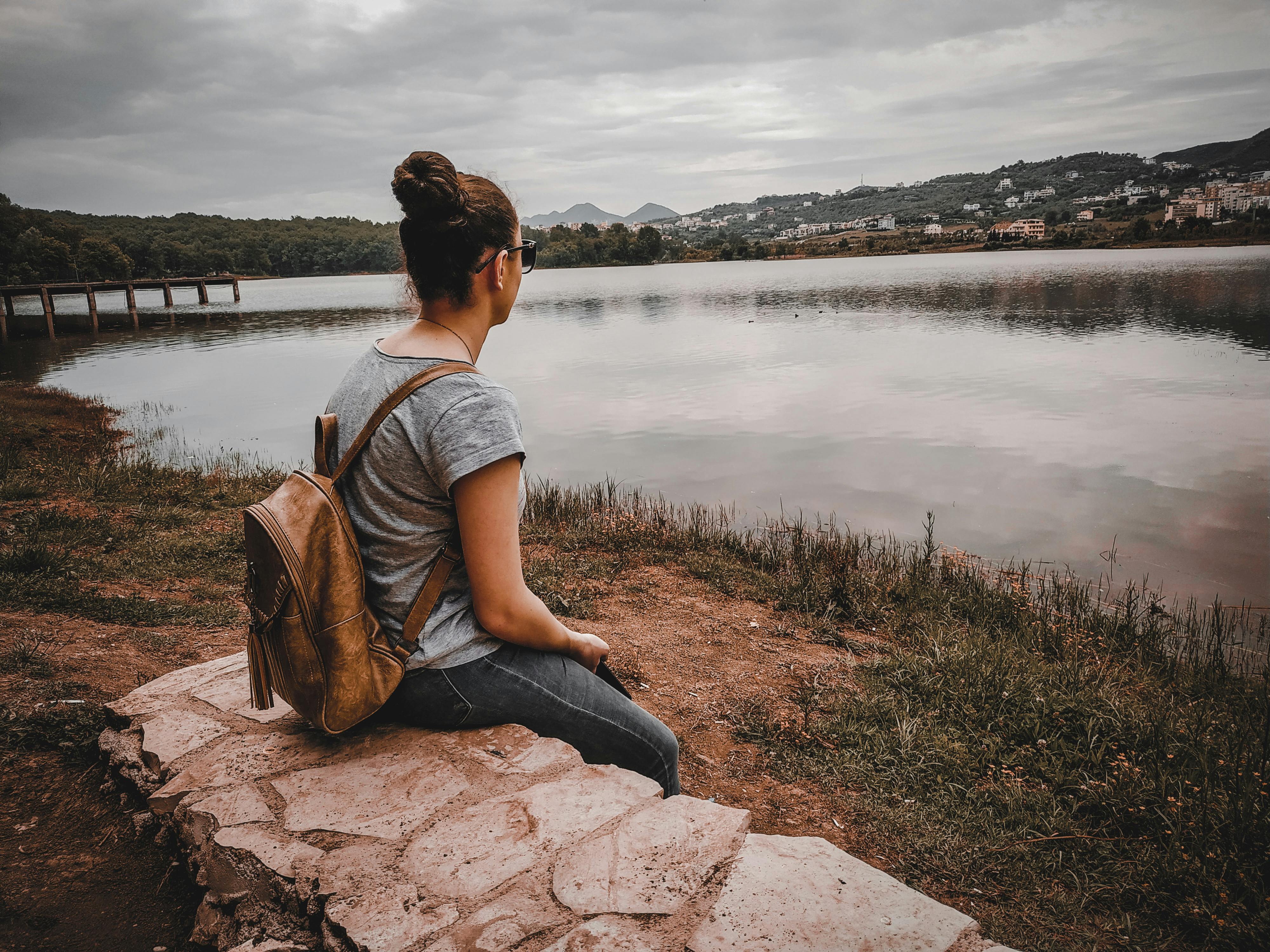 Foto De Mujer Sentada En La Pared De Piedra Mientras Mira Hacia El Lago ...