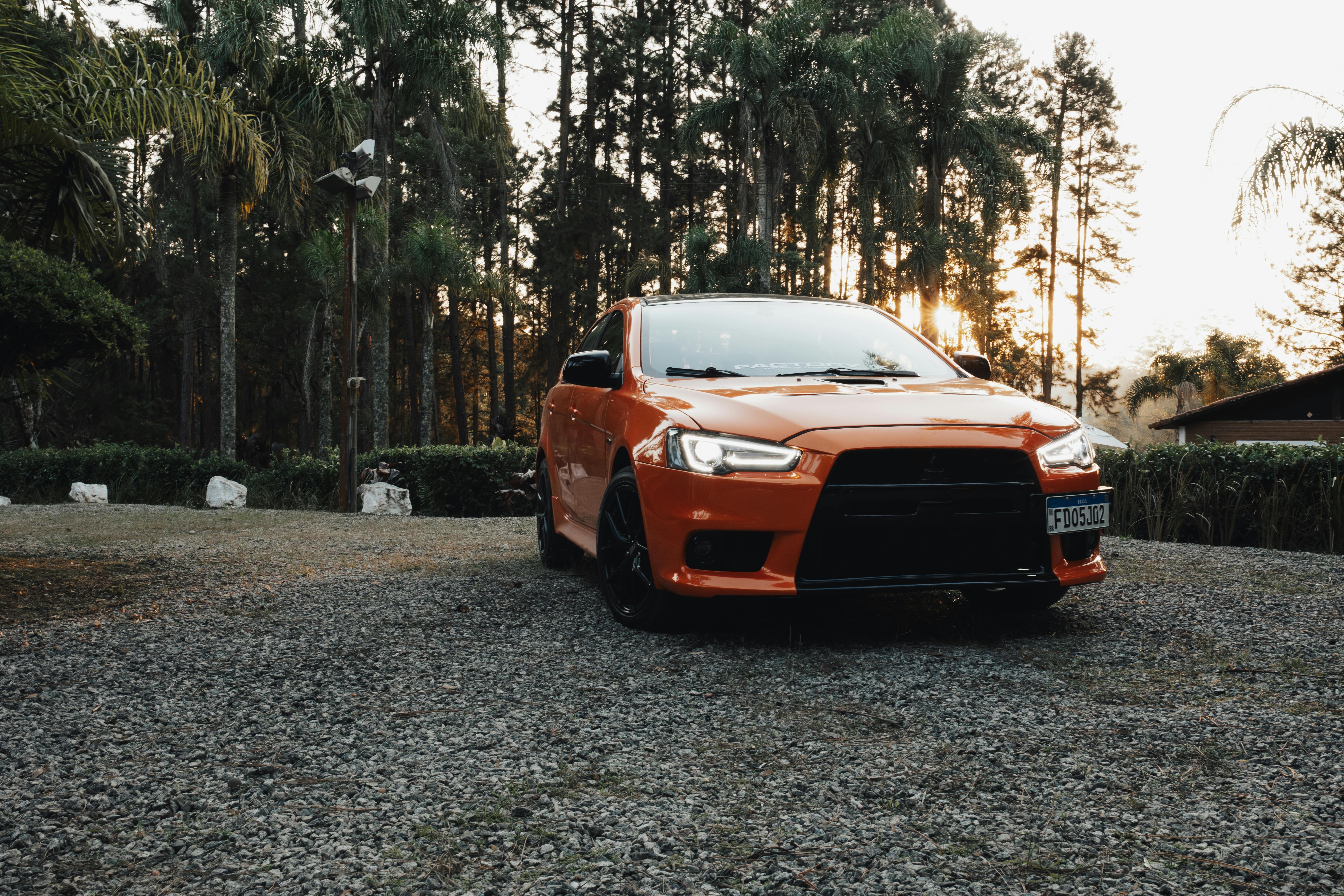 Orange Mitsubishi Lancer Near Trees · Free Stock Photo