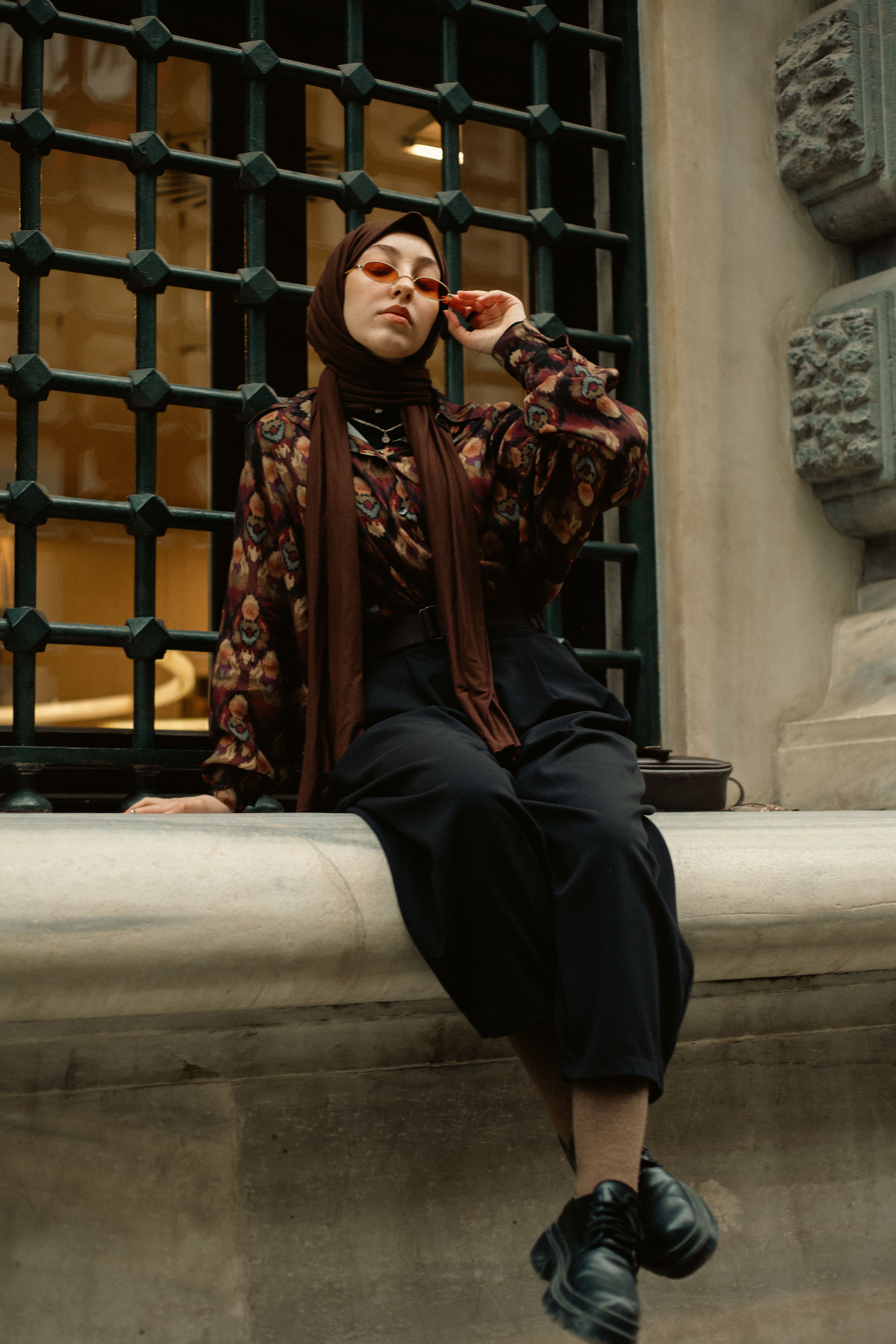 A woman sitting on a ledge wearing a hijab · Free Stock Photo