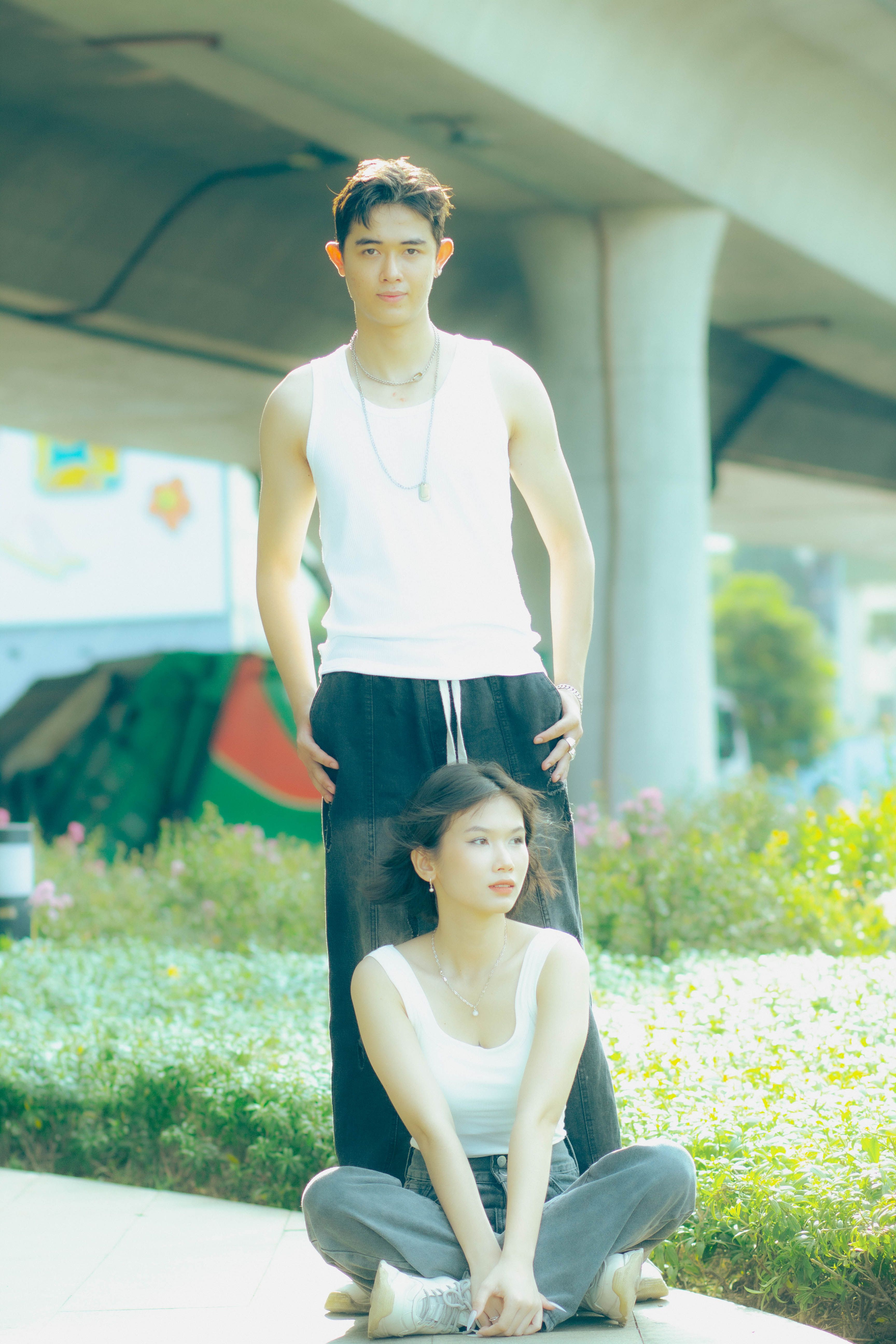 Man Standing Behind Woman Sitting on Pavement · Free Stock Photo