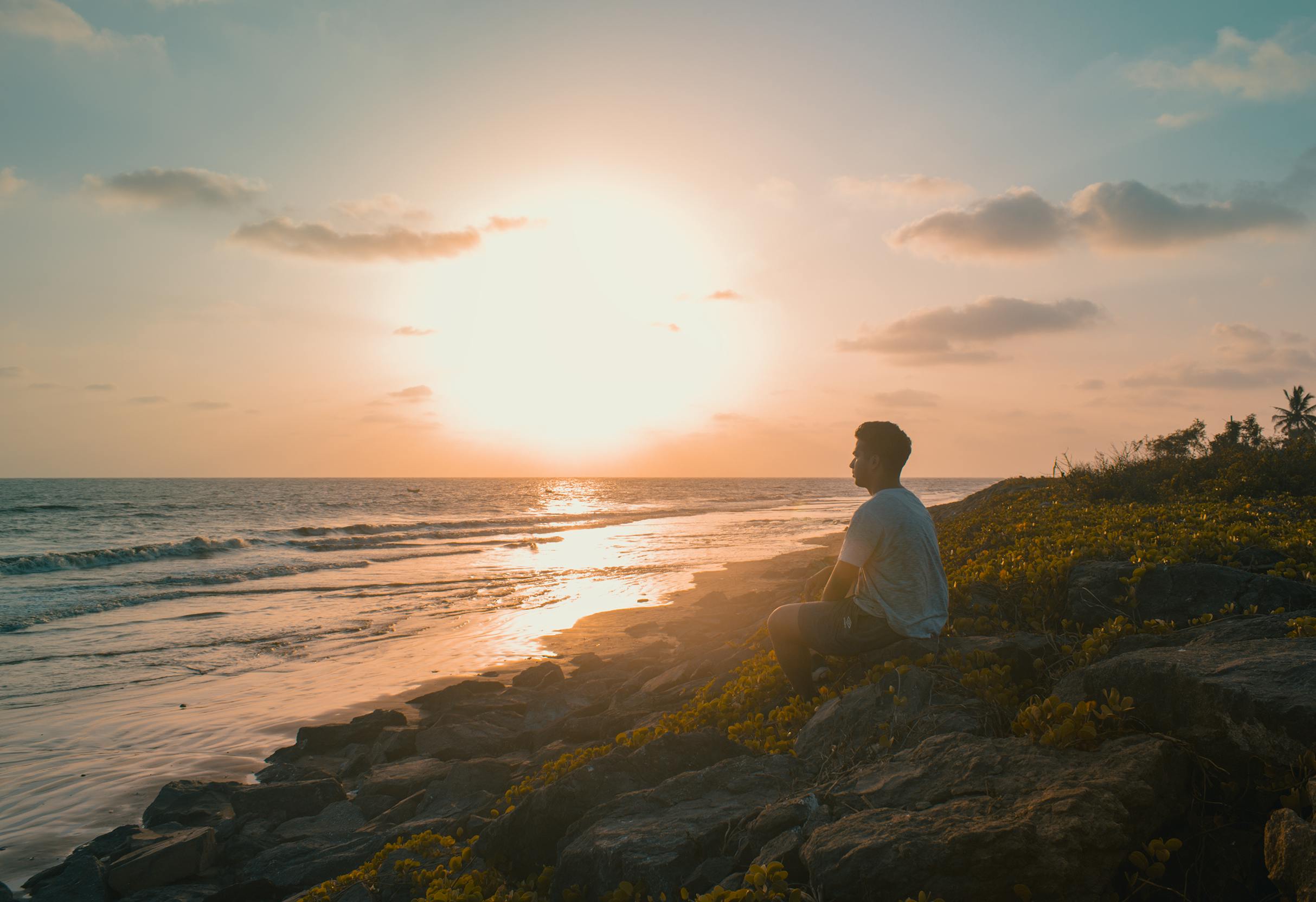 Man Sitting on Rocks Near Body of Water · Free Stock Photo
