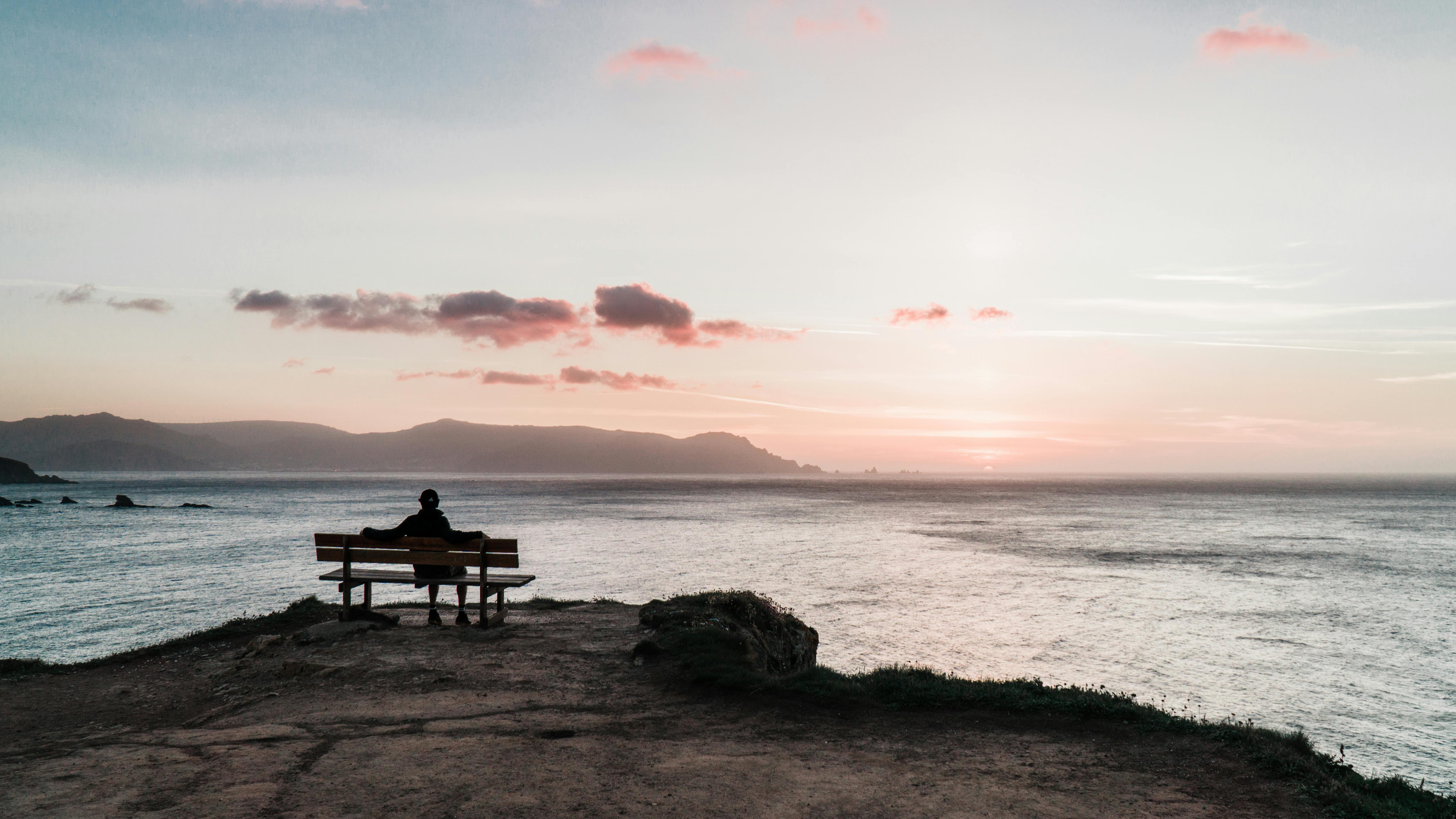 Person Sitting on Bench Facing the Sea · Free Stock Photo
