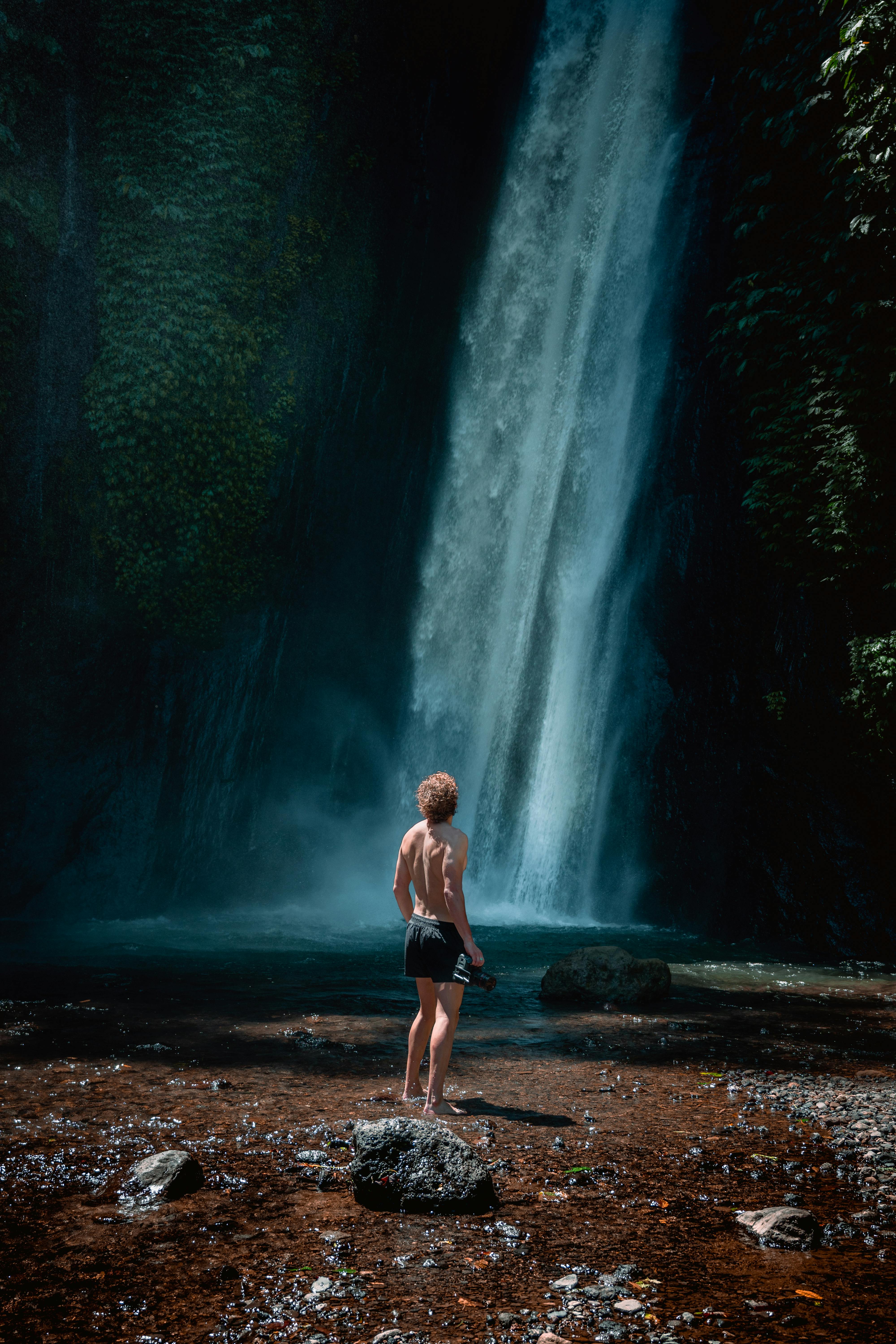 Photo of Man Standing on Rocks Near Waterfalls · Free Stock Photo