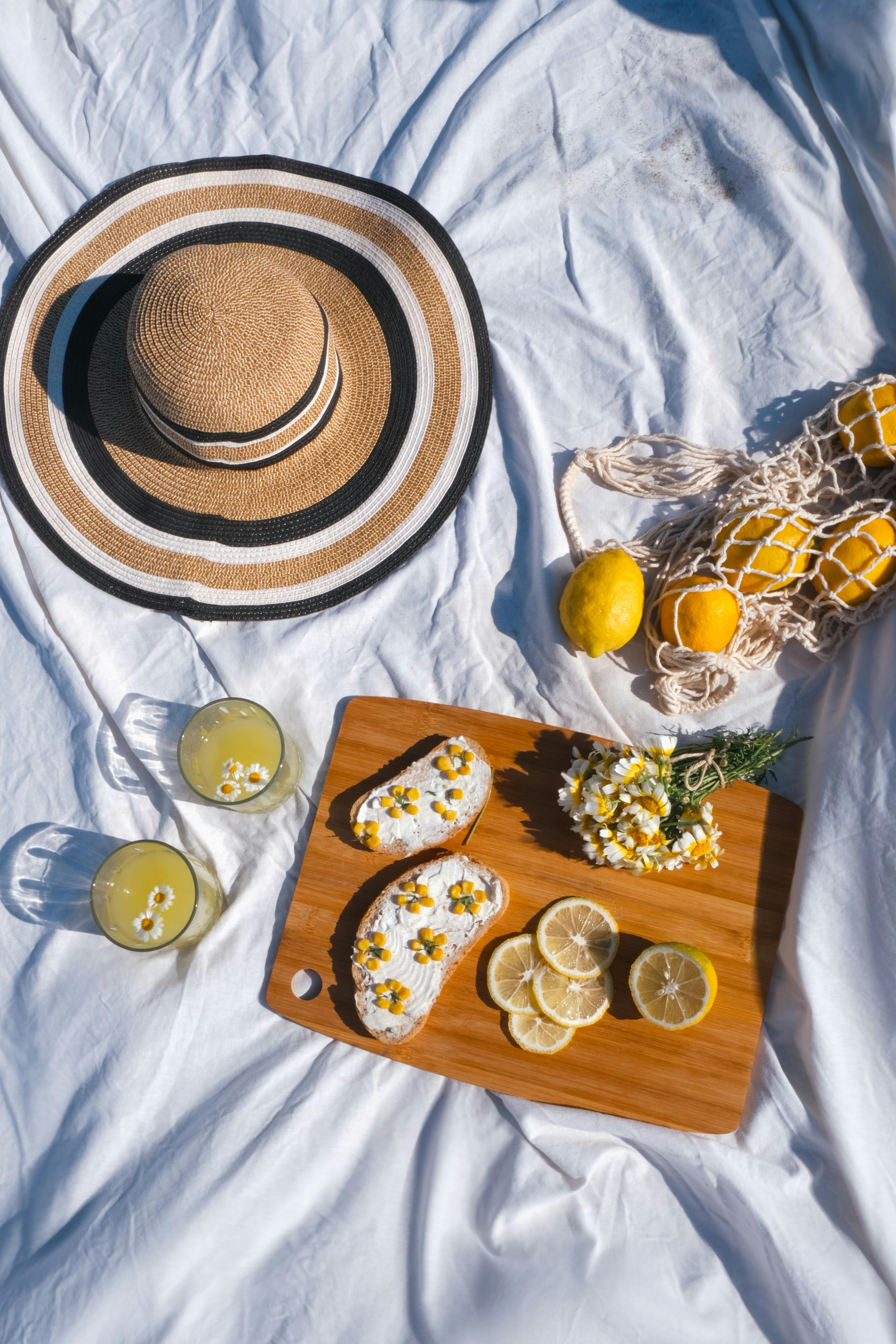 Food, Drinks and a Sunhat on a Blanket in Sunlight · Free Stock Photo