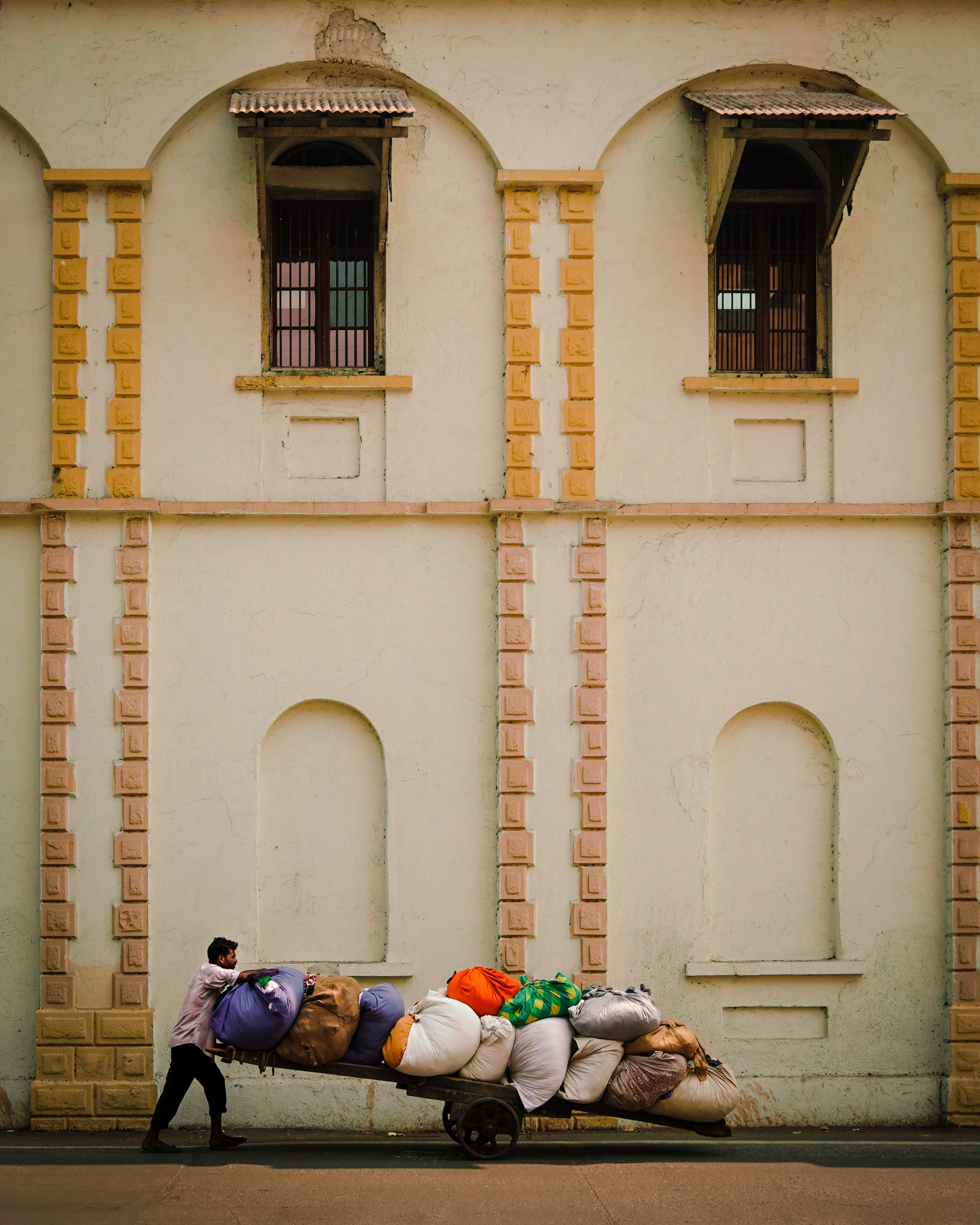 A Man Pushing a Cart Loaded with Bags · Free Stock Photo