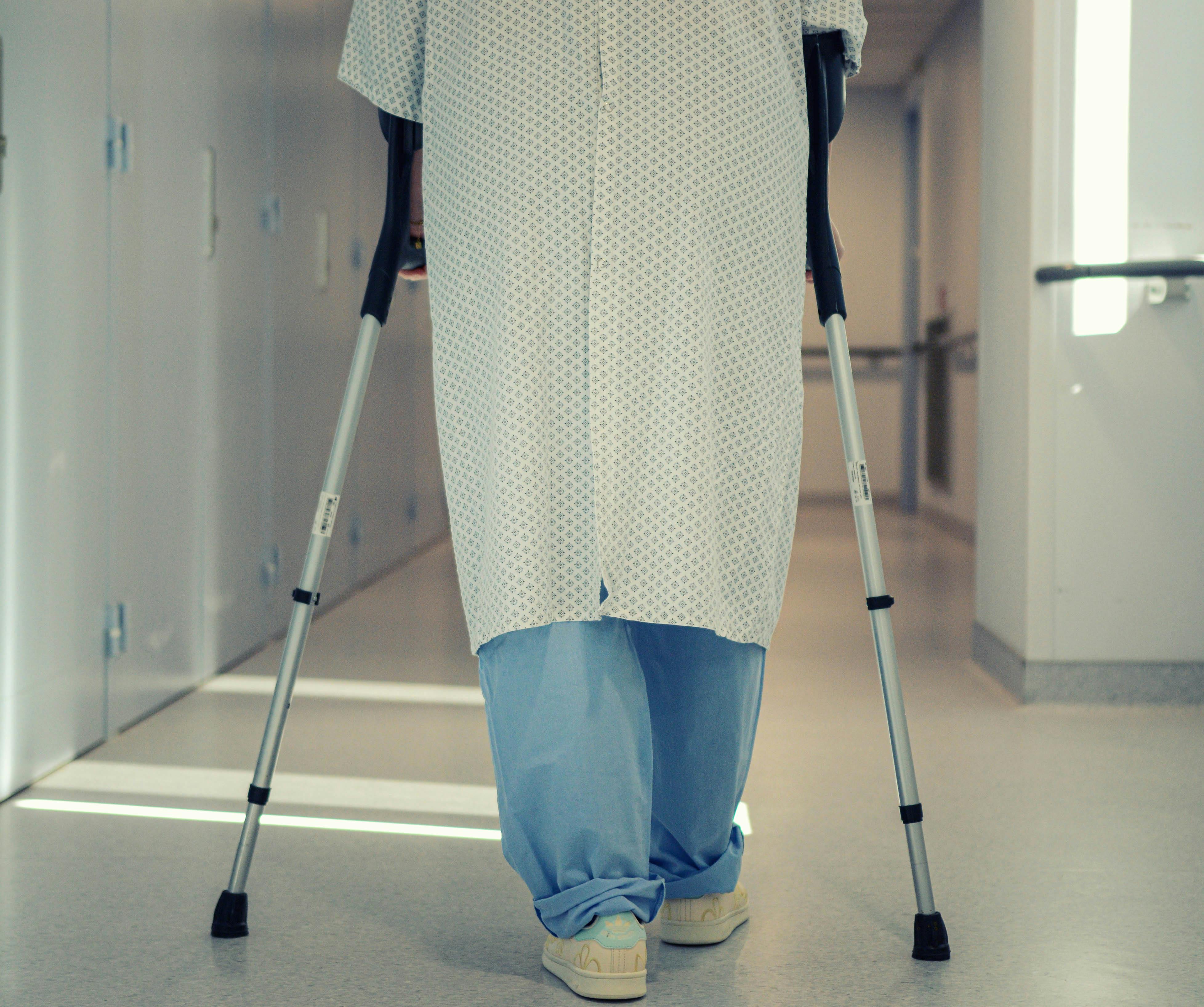 Rear View of a Patient Walking With Crutches on a Hospital Corridor ...