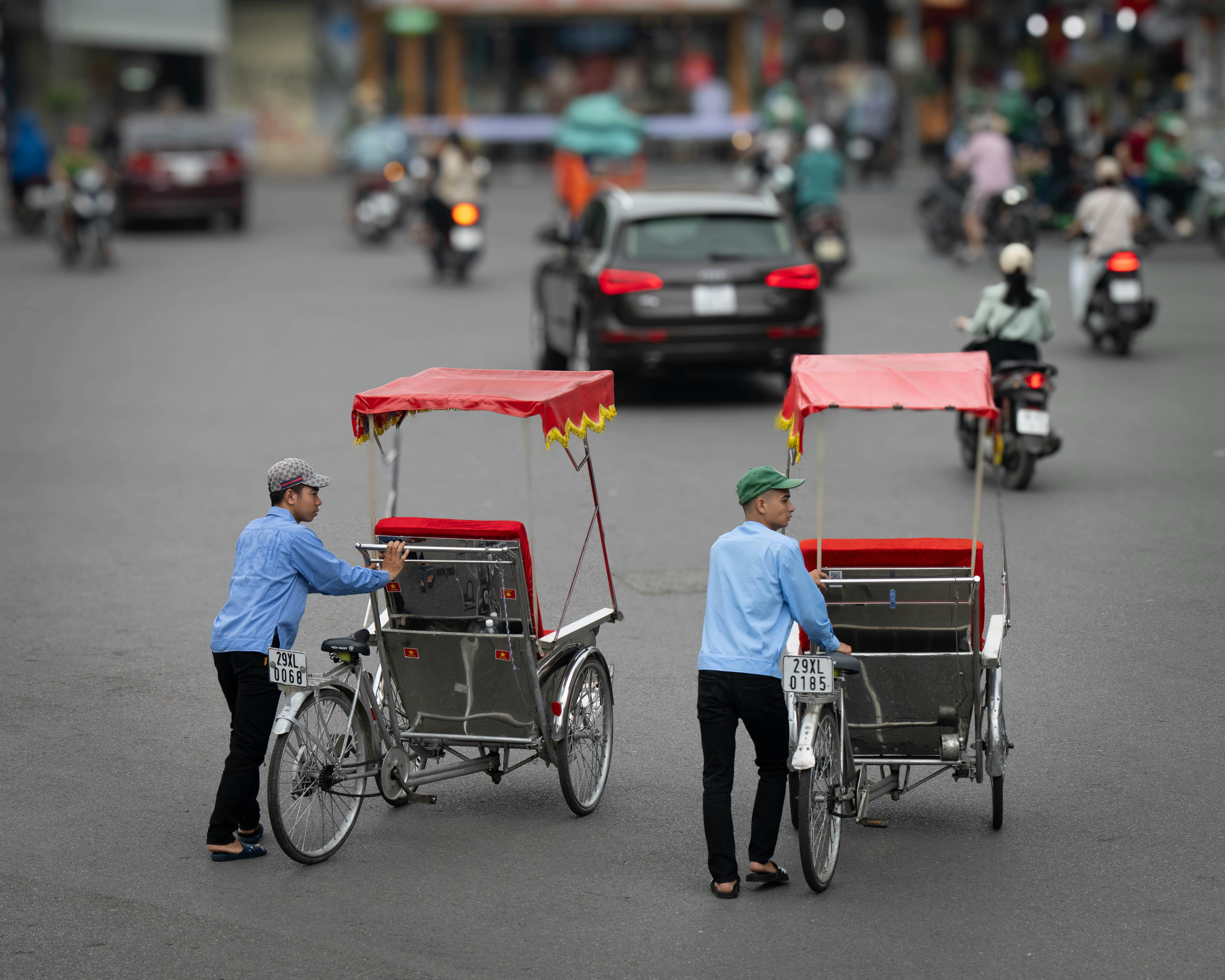 Back View of Two Men Pushing Rickshaws on a Busy Street · Free Stock Photo