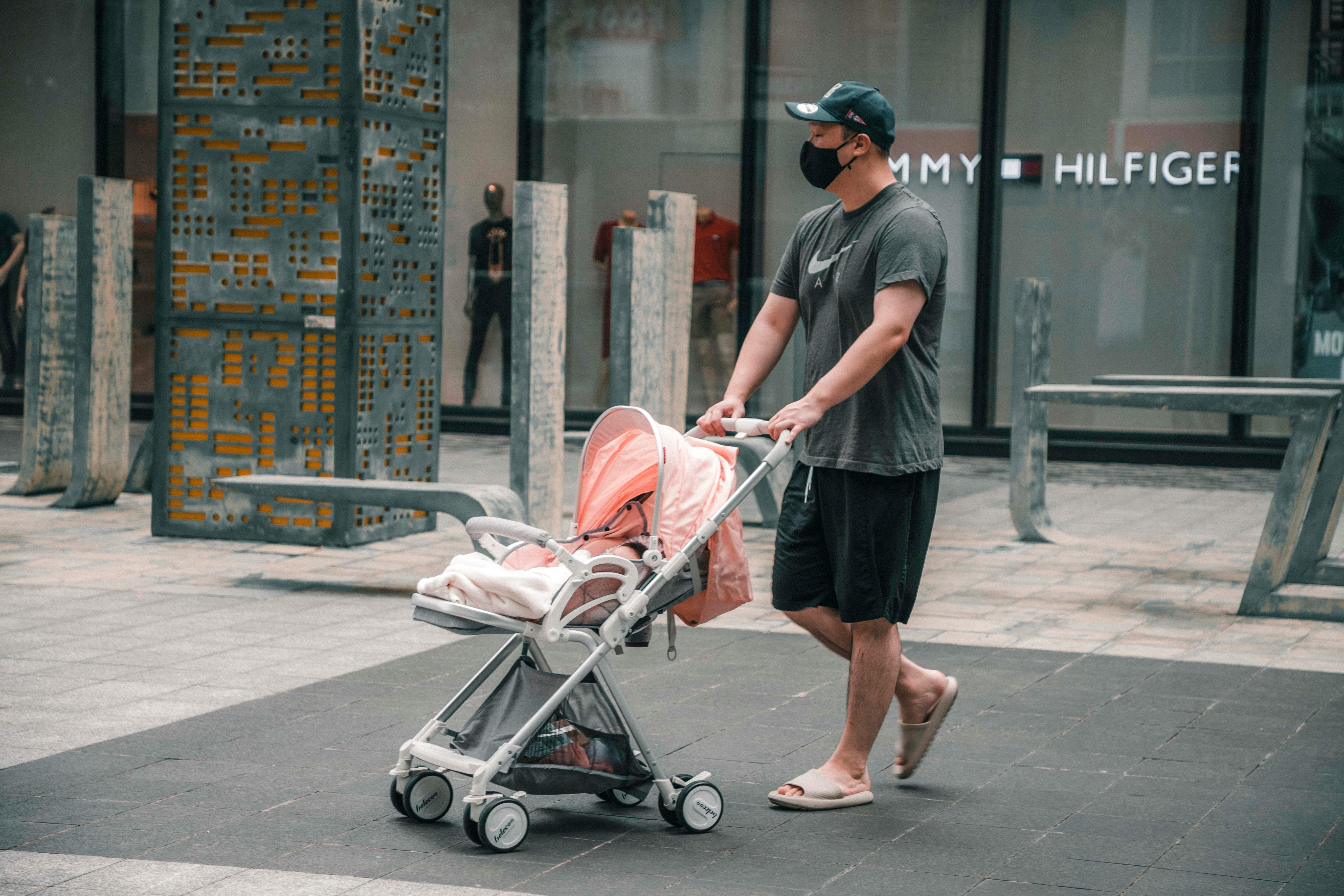 Man in Black Face Mask Pulling Stroller · Free Stock Photo