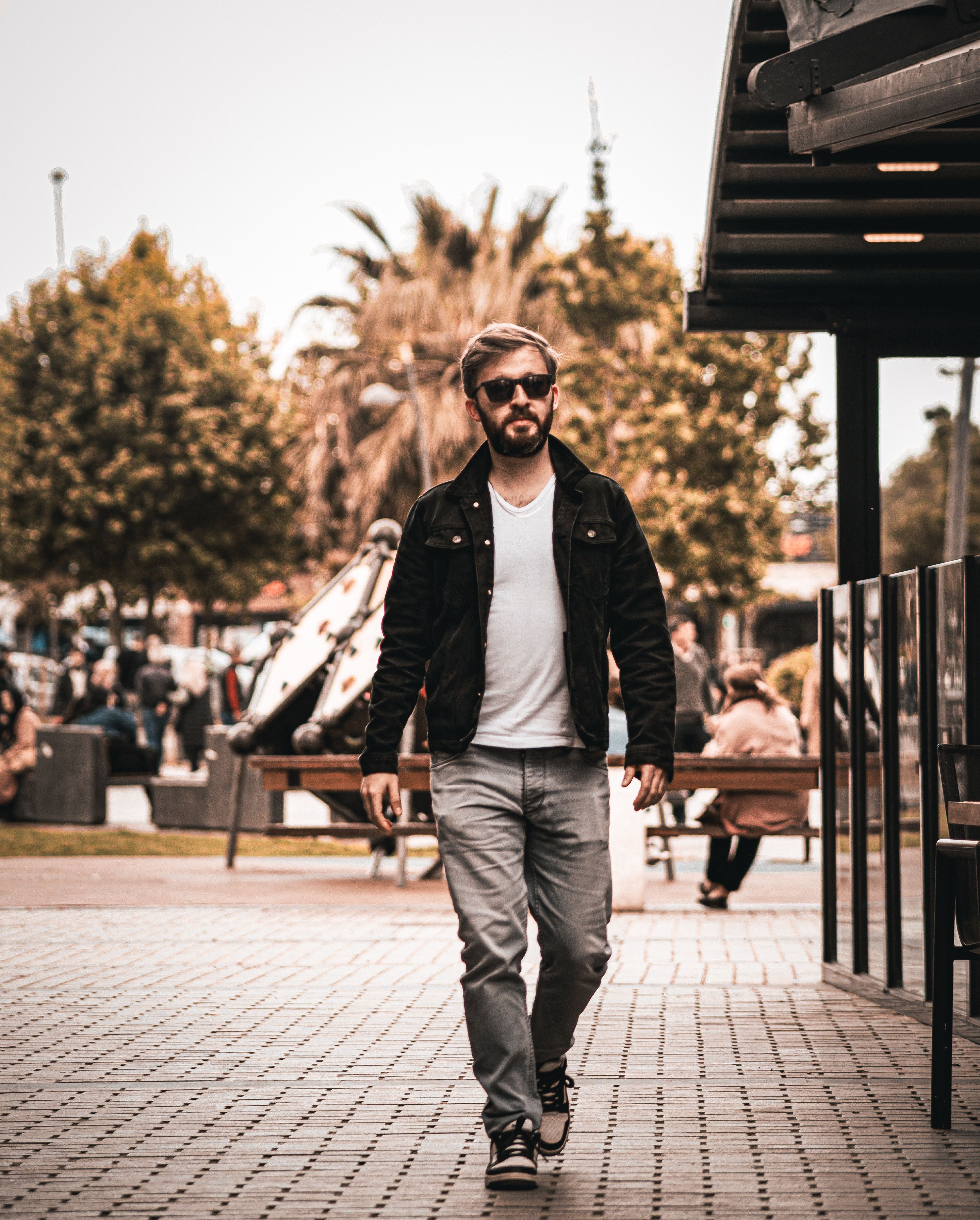 A man walking down a sidewalk with a beard · Free Stock Photo