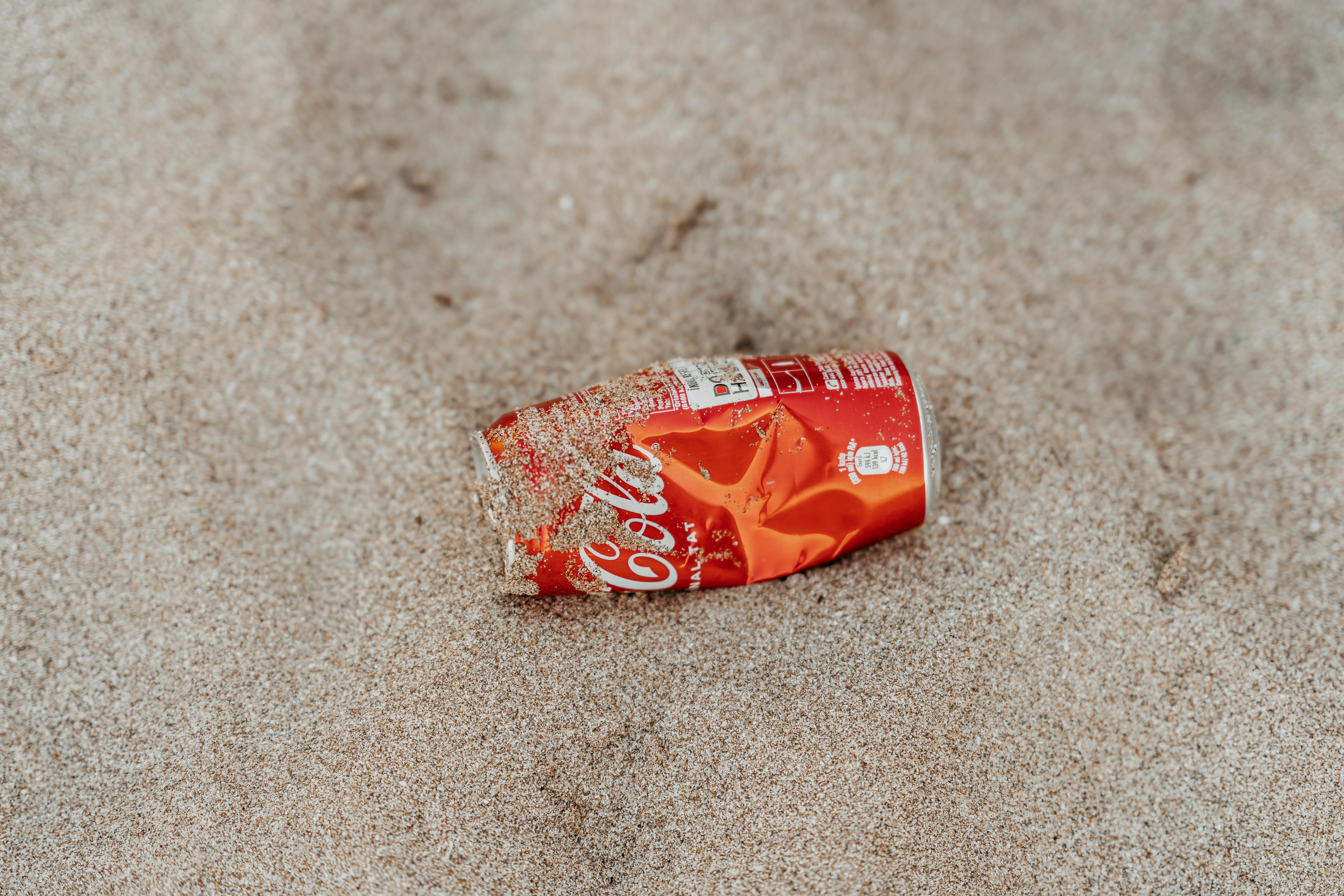 A soda can laying in the sand · Free Stock Photo