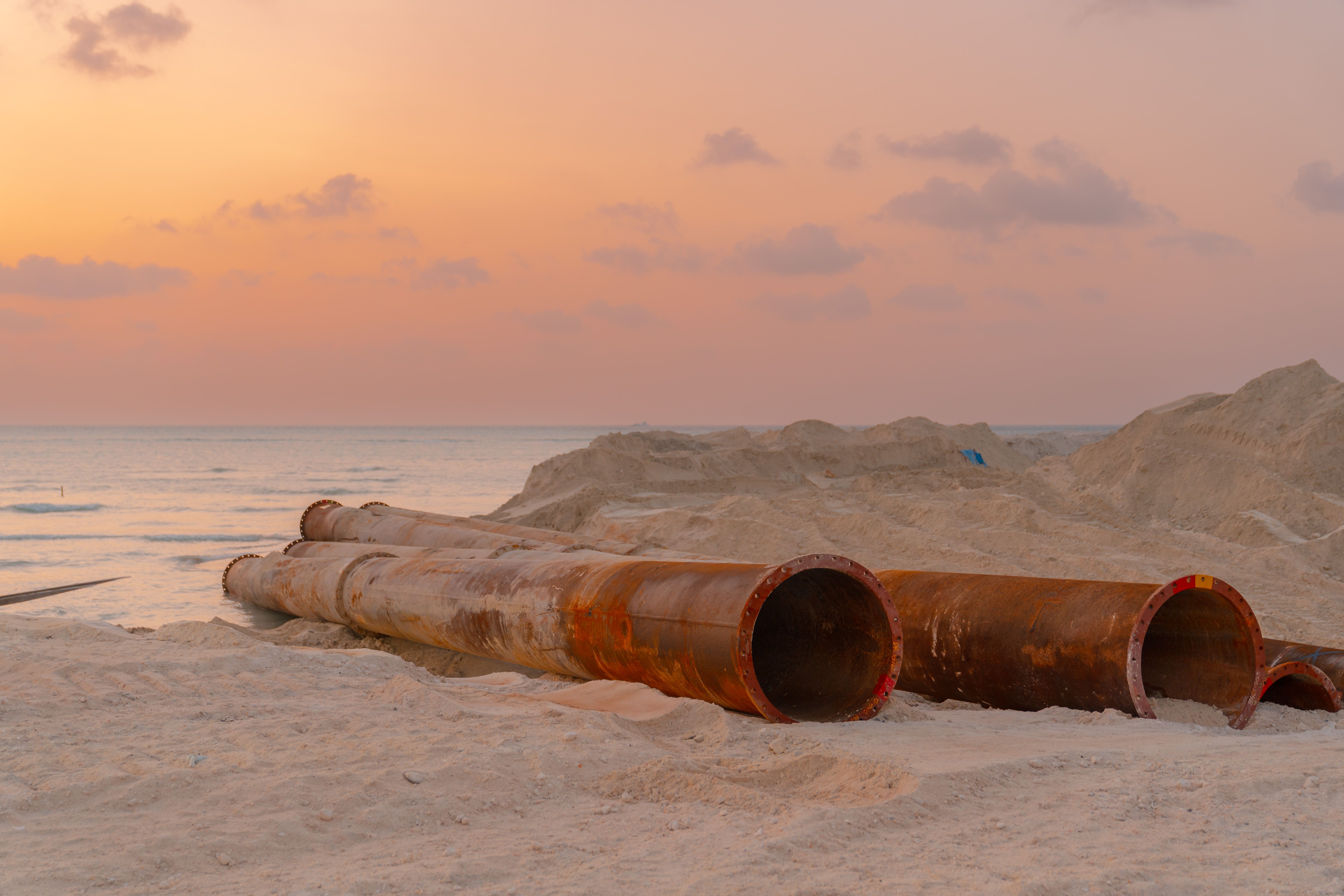 Large pipes laid out on a beach construction site during a beautiful ...