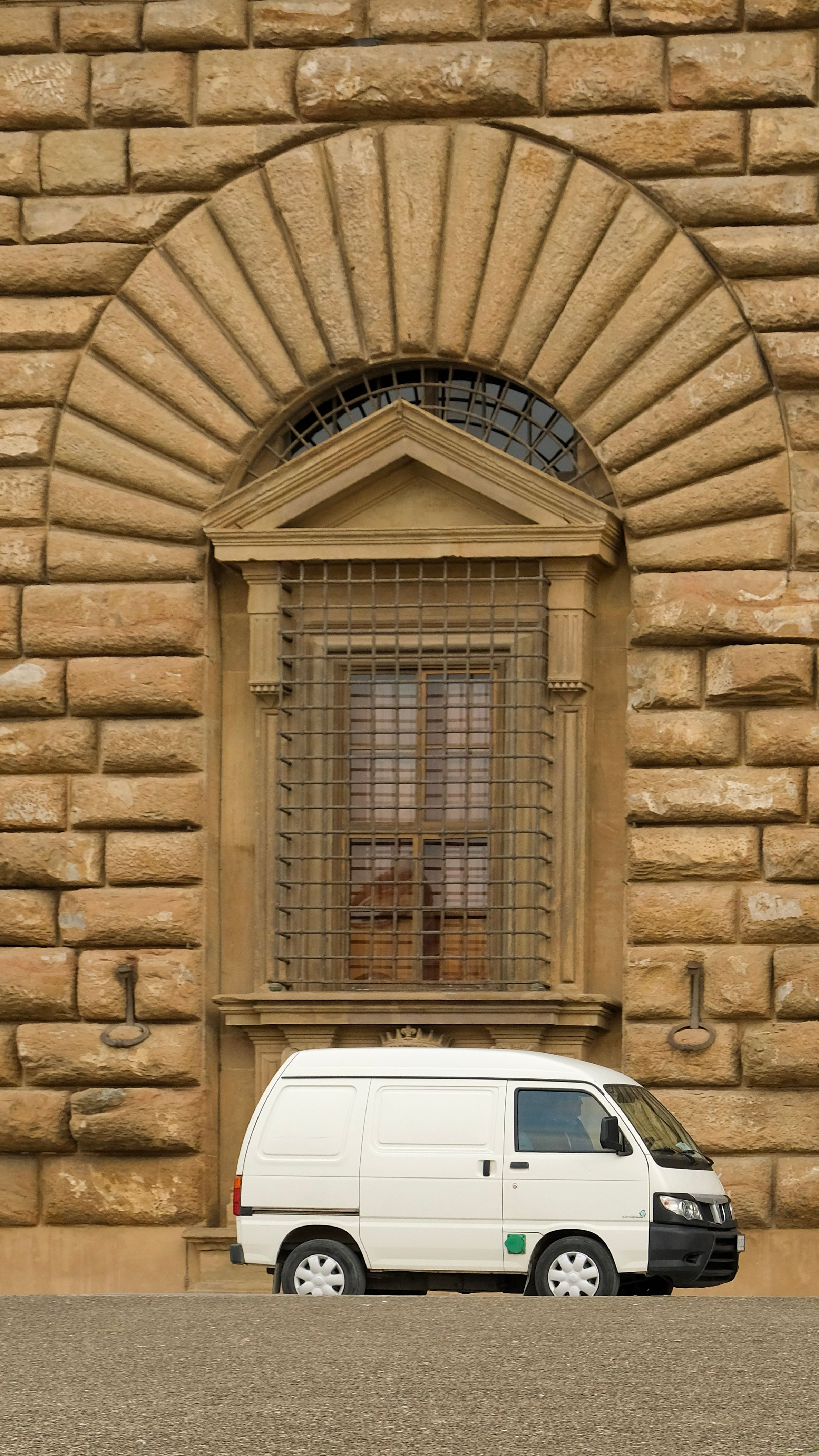 A white van parked in front of a stone building · Free Stock Photo
