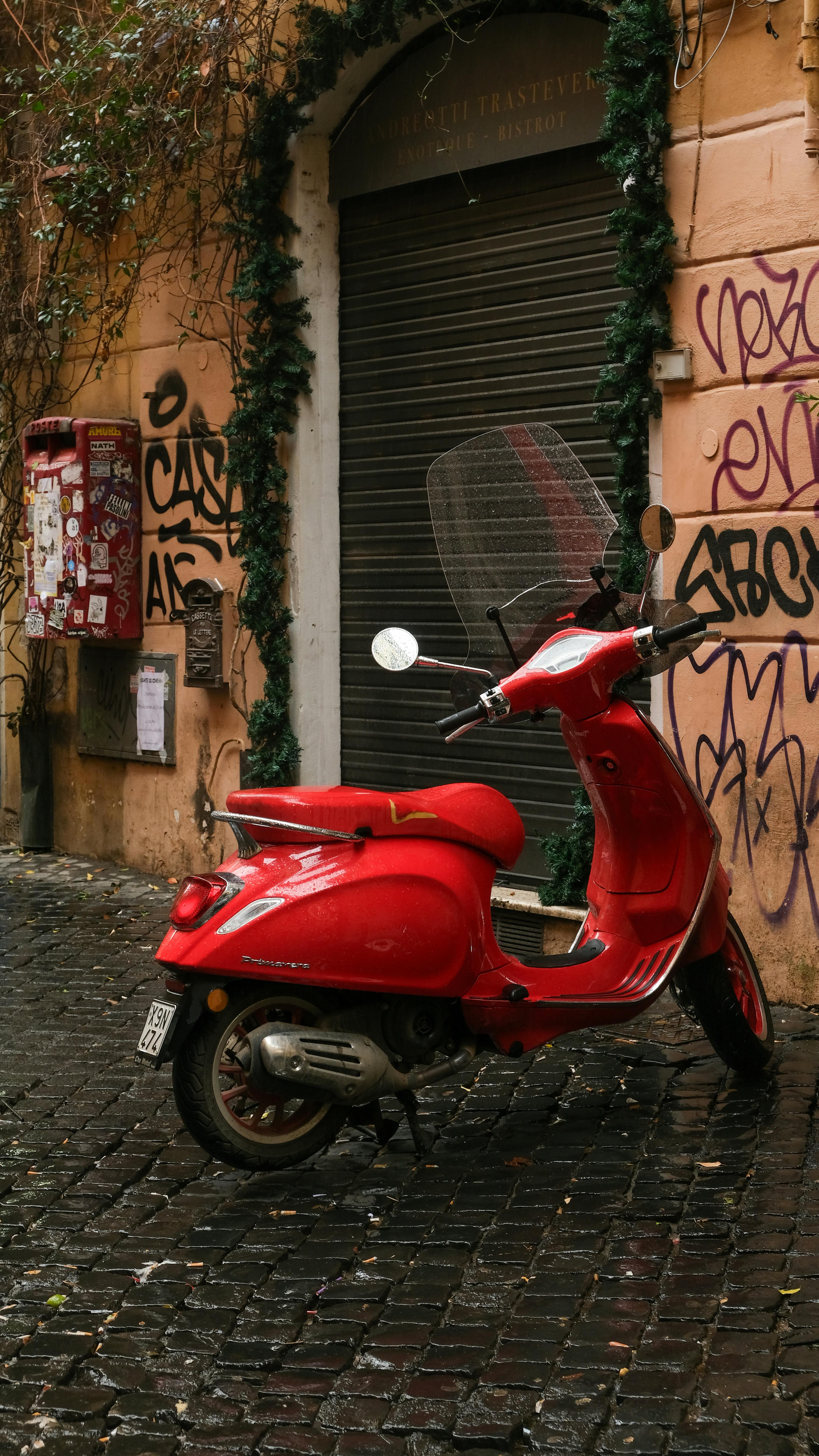 A Red Vespa Motor Scooter Parked near a Building · Free Stock Photo