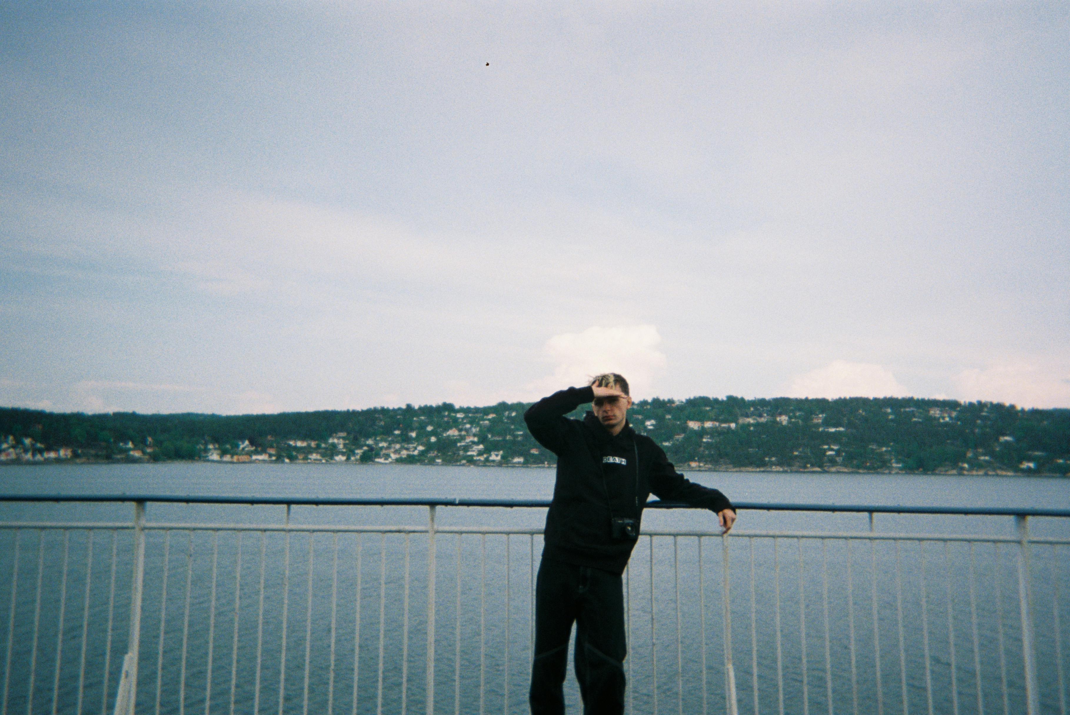 Man Leaning on Railing on Seashore · Free Stock Photo