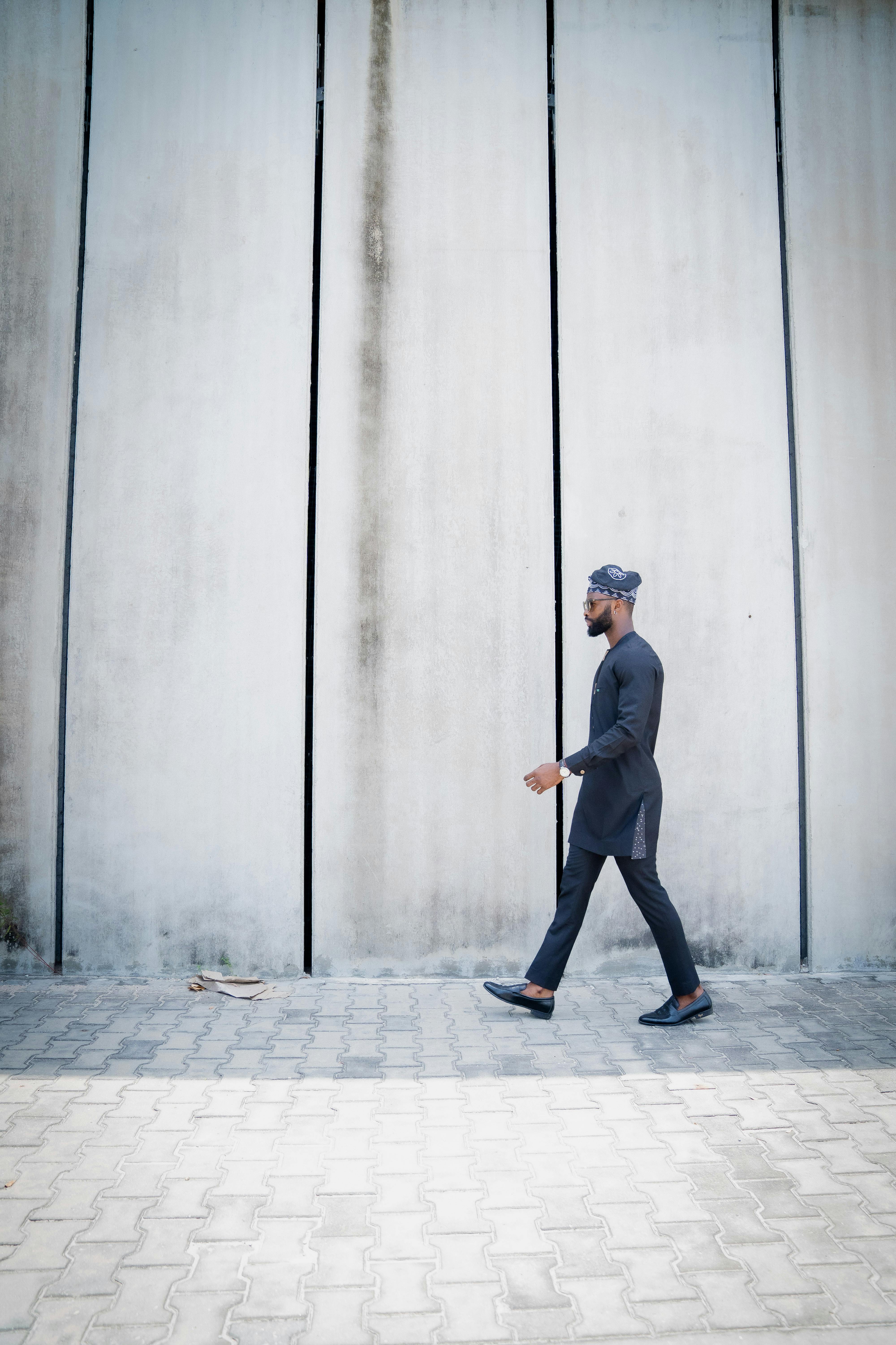 Man in Gray Clothes Walking near White Wall · Free Stock Photo