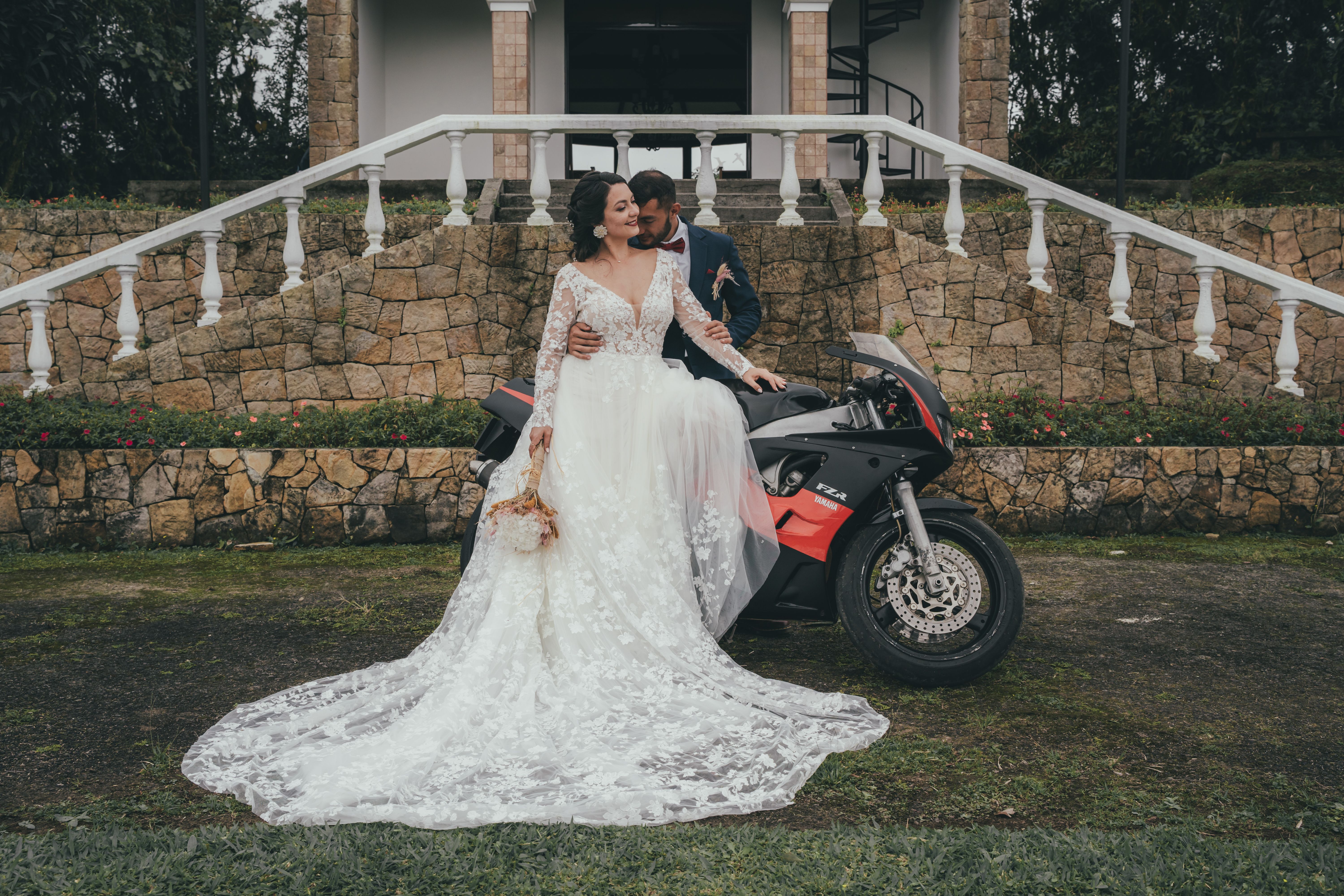 A bride and groom pose on a motorcycle · Free Stock Photo