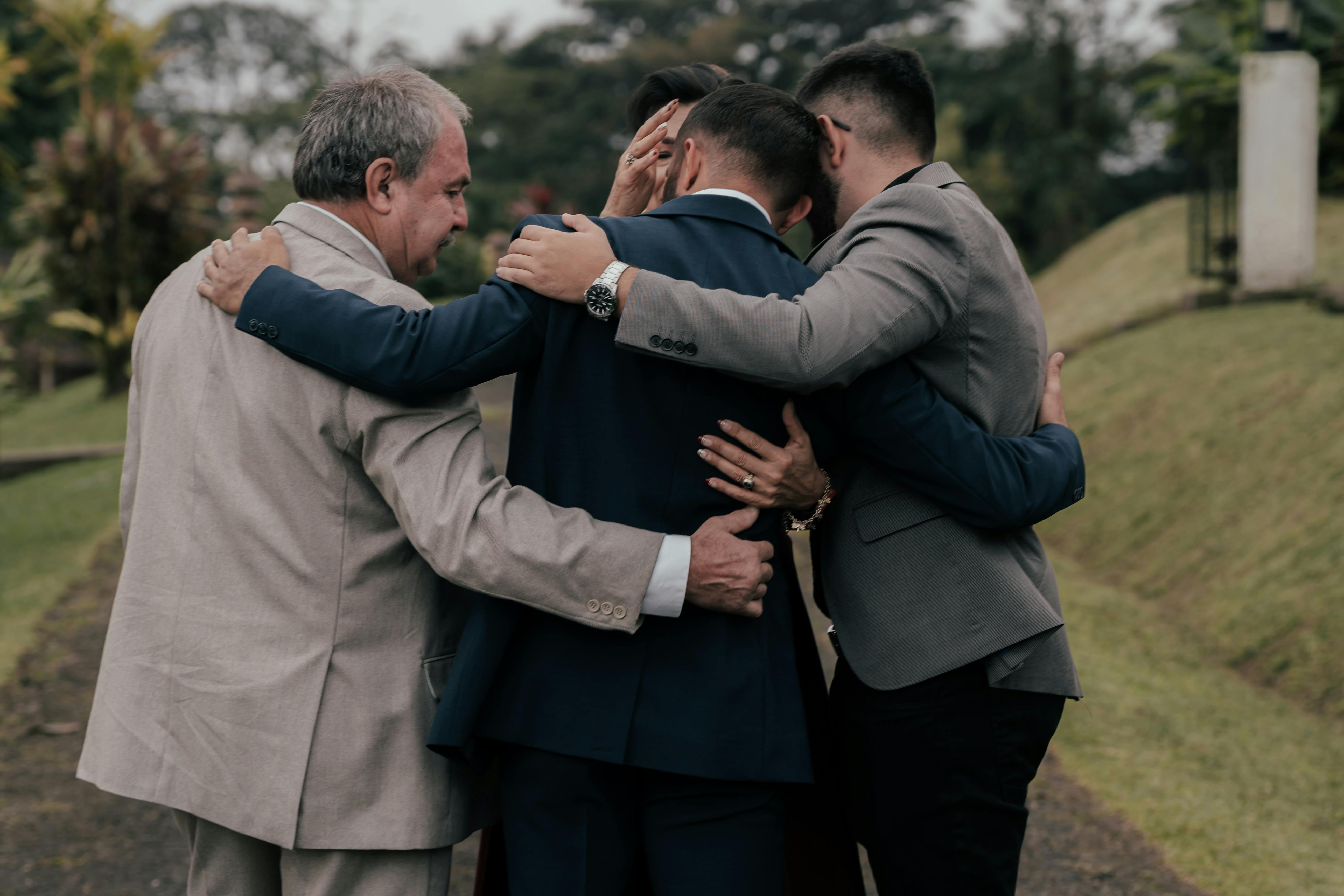 Three men hugging each other on a path · Free Stock Photo