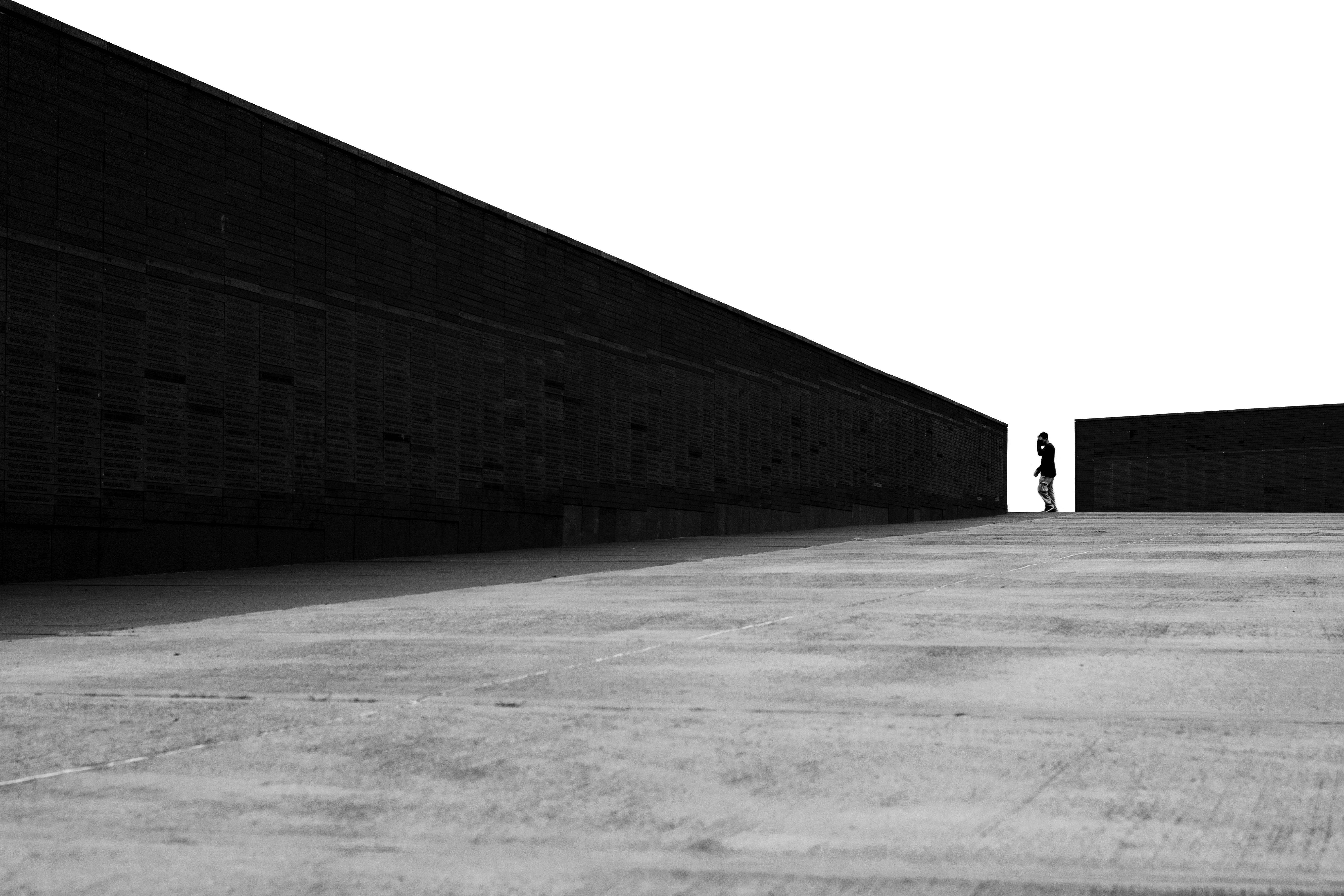 Grayscale Photo of Man Walking on Street Near Buildings · Free Stock Photo