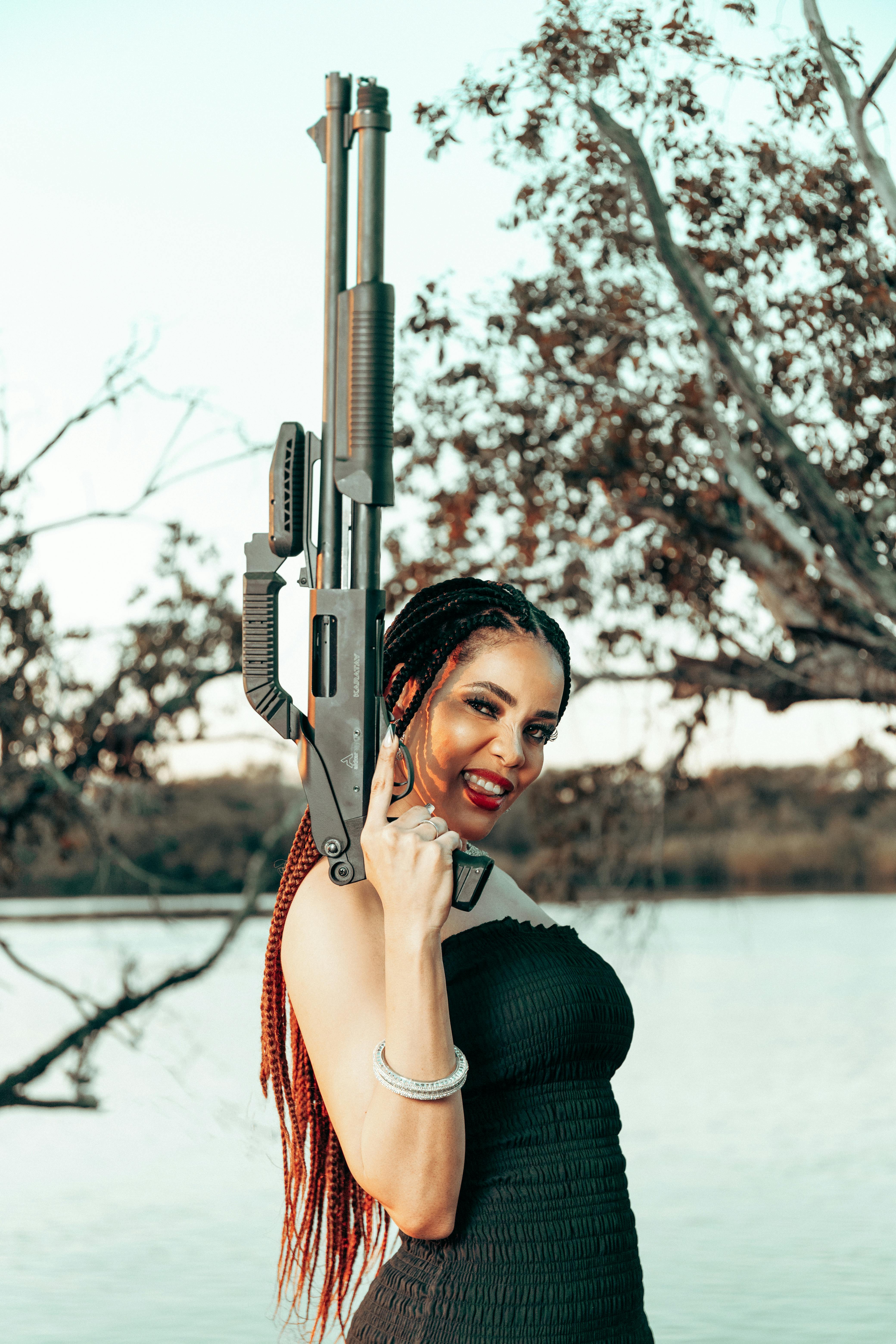 Smiling Woman Holding Machine Gun · Free Stock Photo