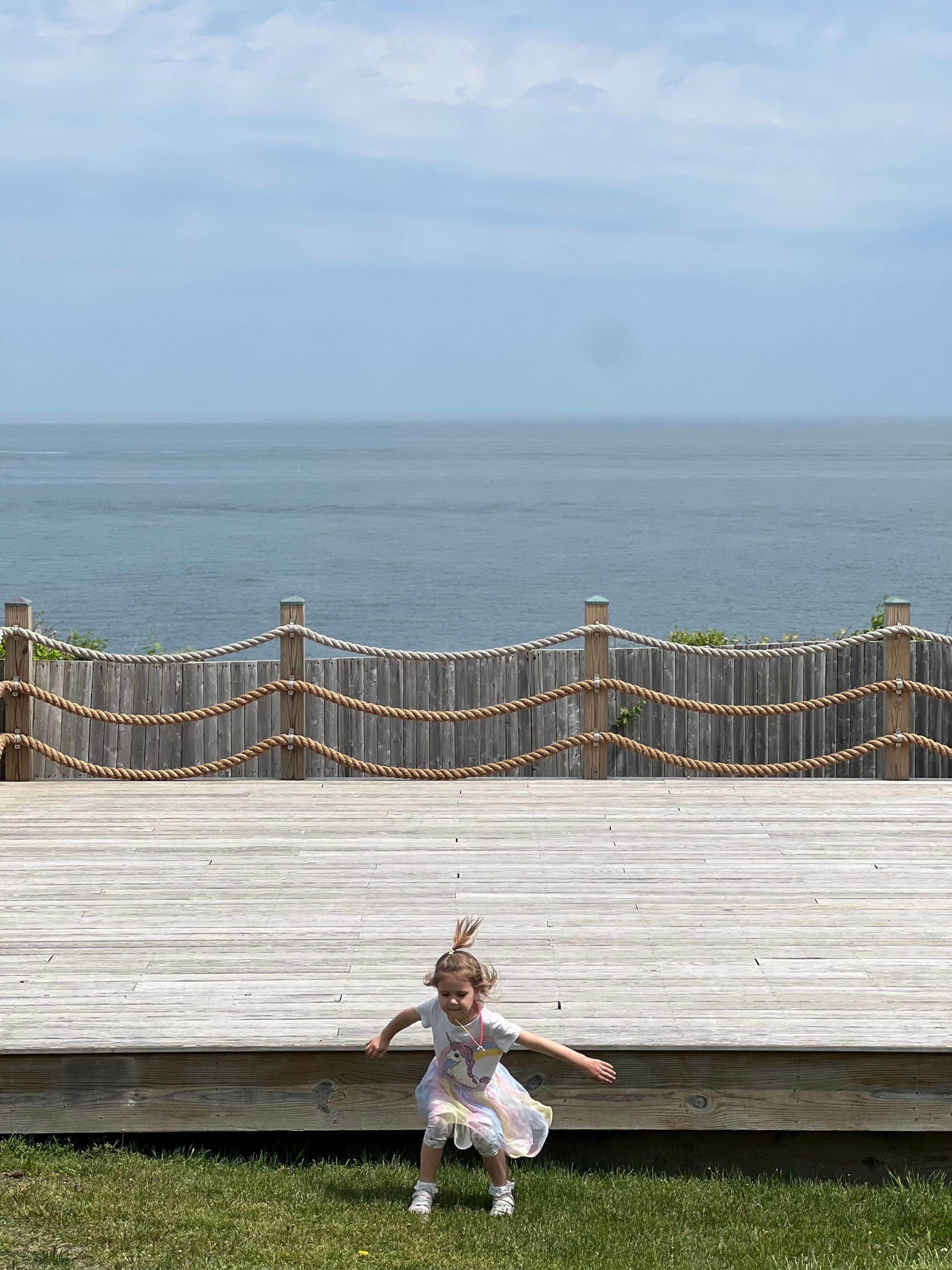 A Little Girl Standing next to a Wooden Deck on a Shore · Free Stock Photo