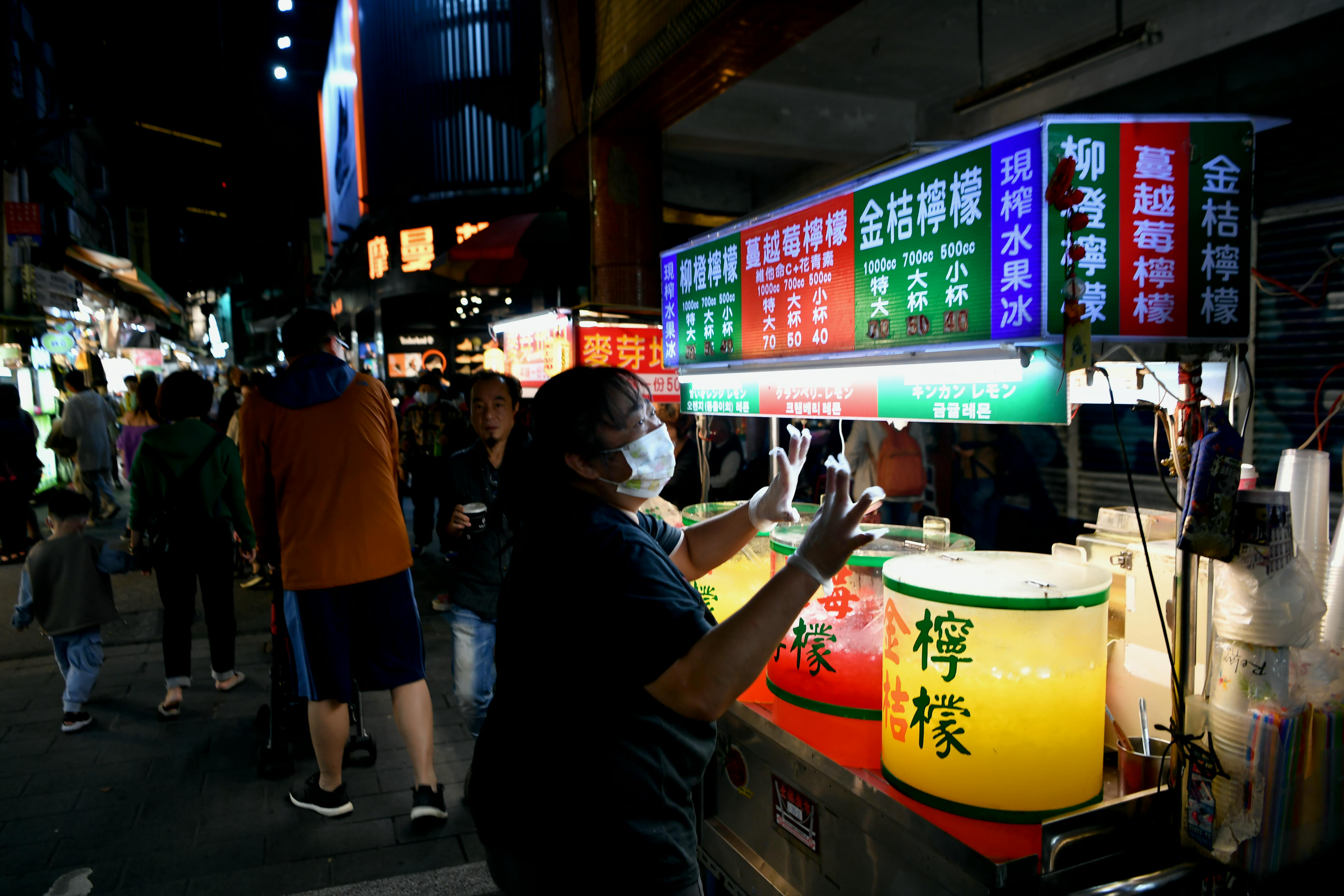 A woman is standing in front of a food stand · Free Stock Photo