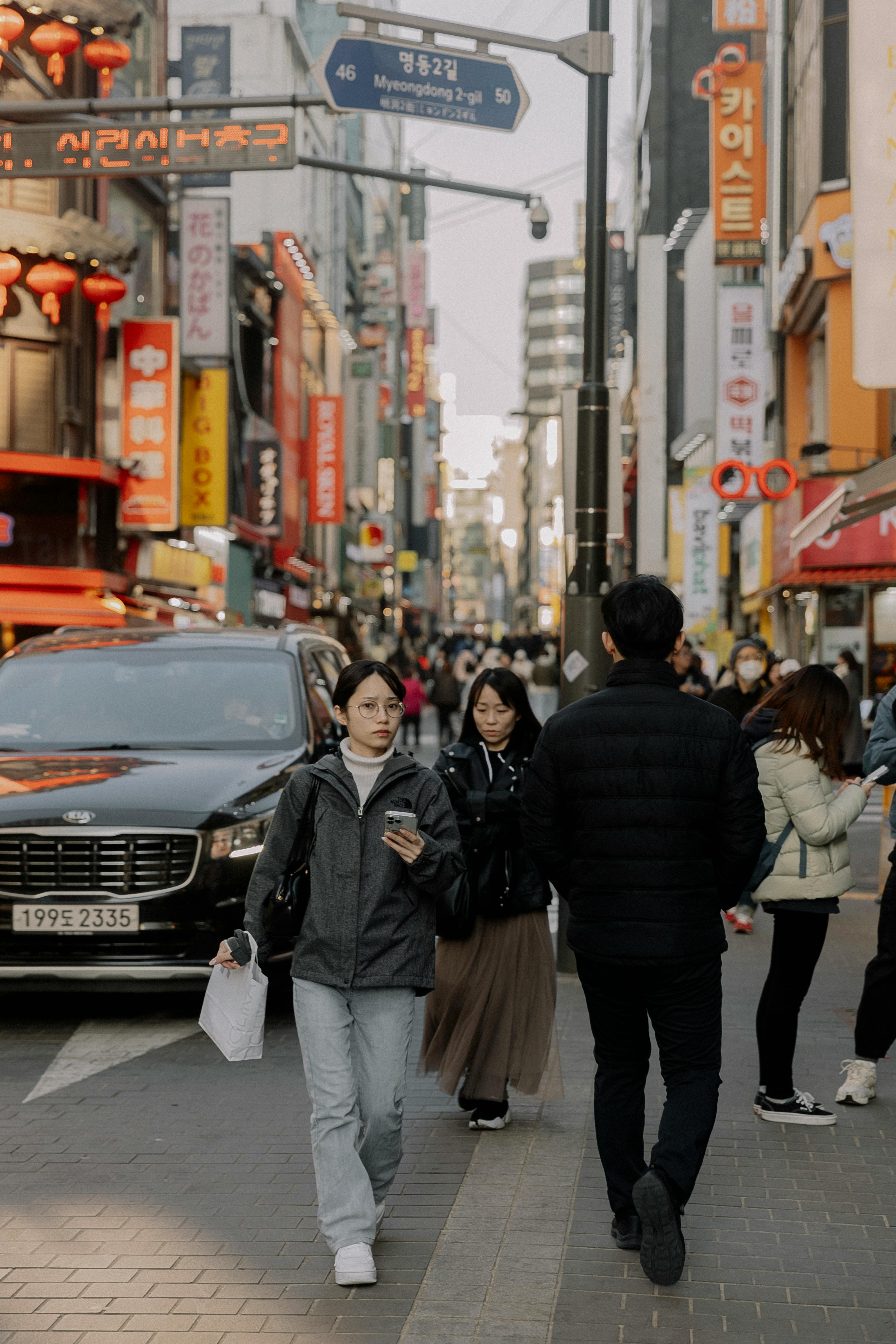 People Walking Through the Street of a City by Vehicles and Billboards ...