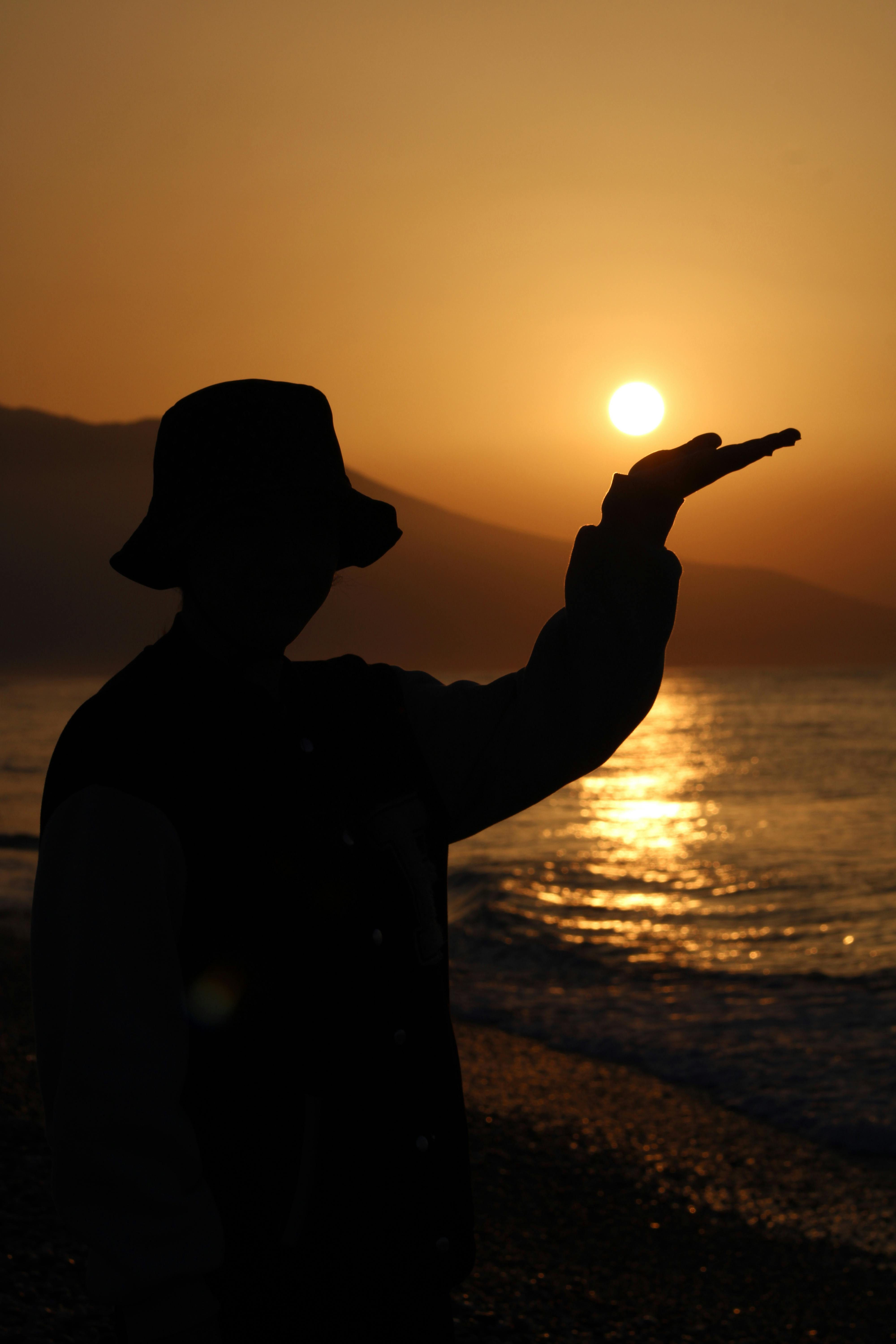 A silhouette of a person pointing at the sun · Free Stock Photo