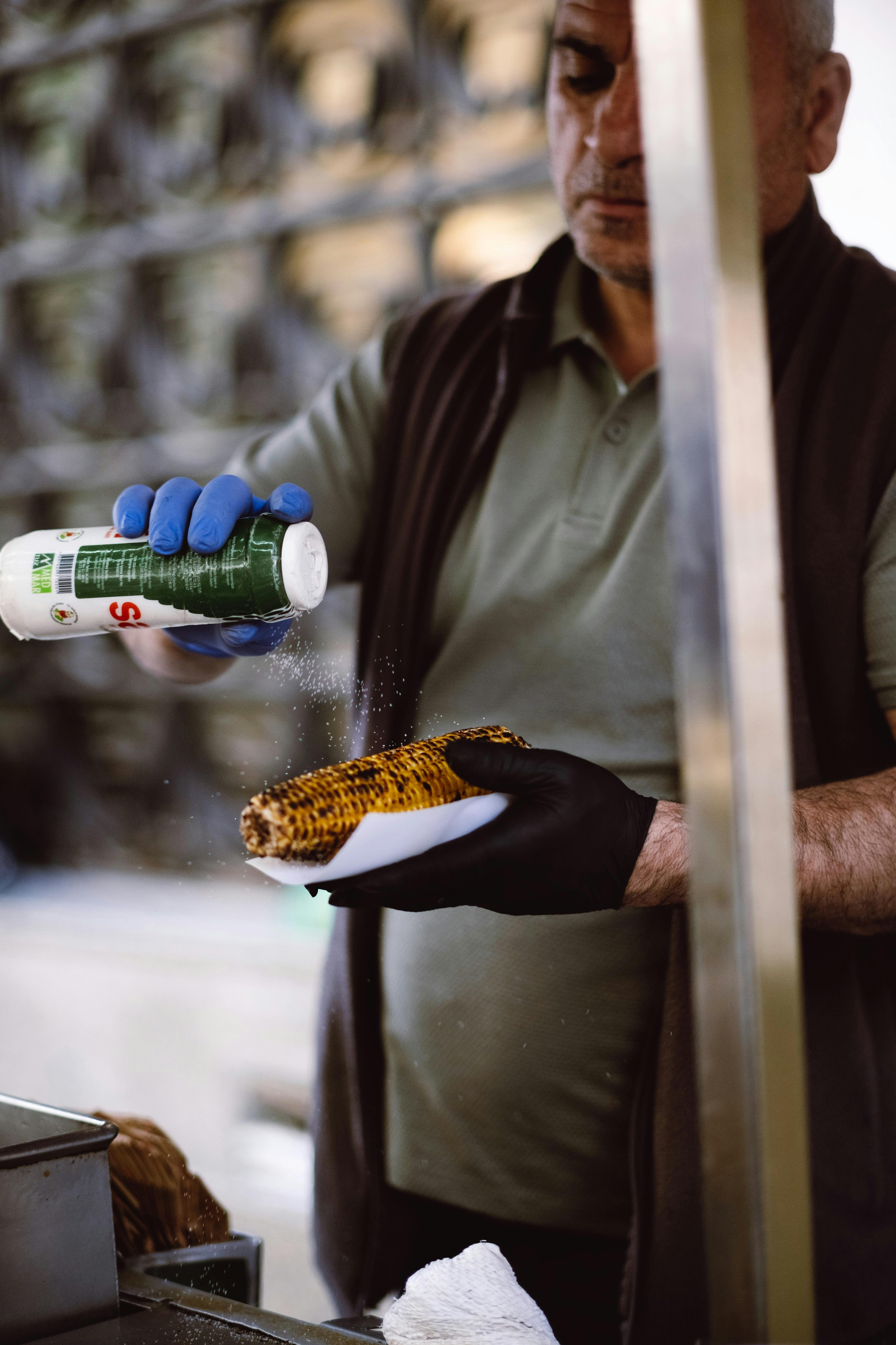 Man Adding Salt to Roasted Corn · Free Stock Photo