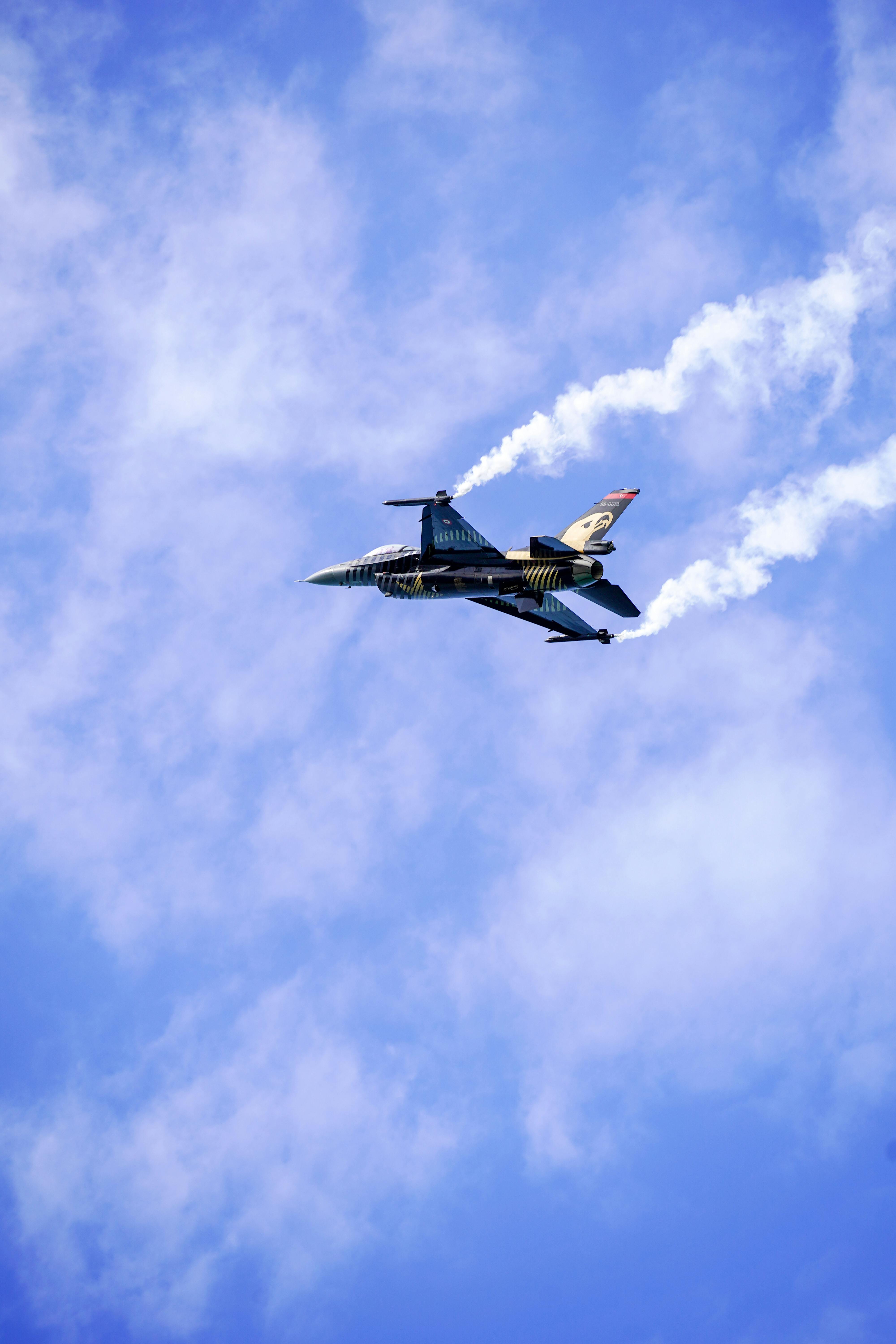 A fighter jet flying through the air with smoke coming out of it · Free ...