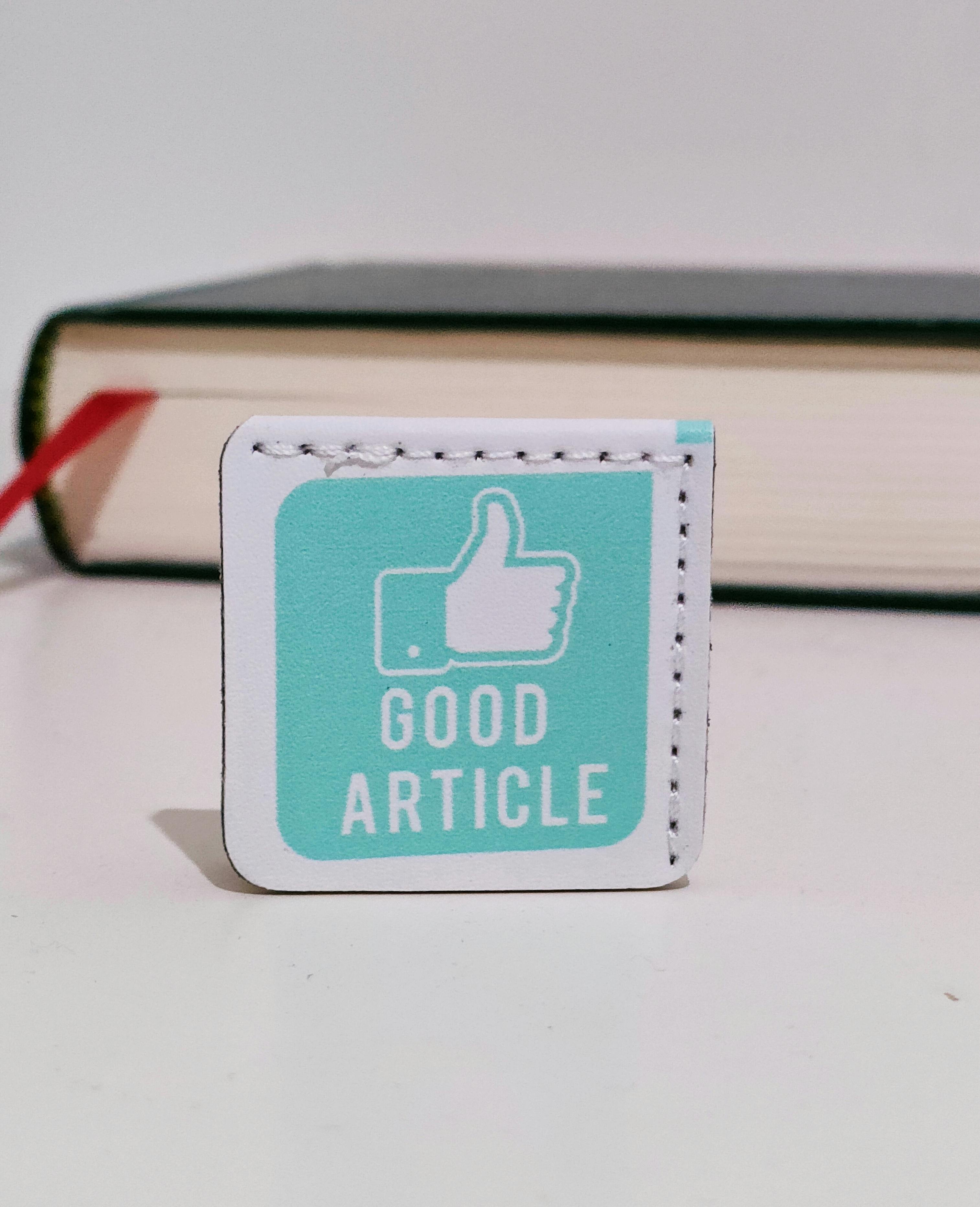 Good Article Badge Standing next to Book · Free Stock Photo