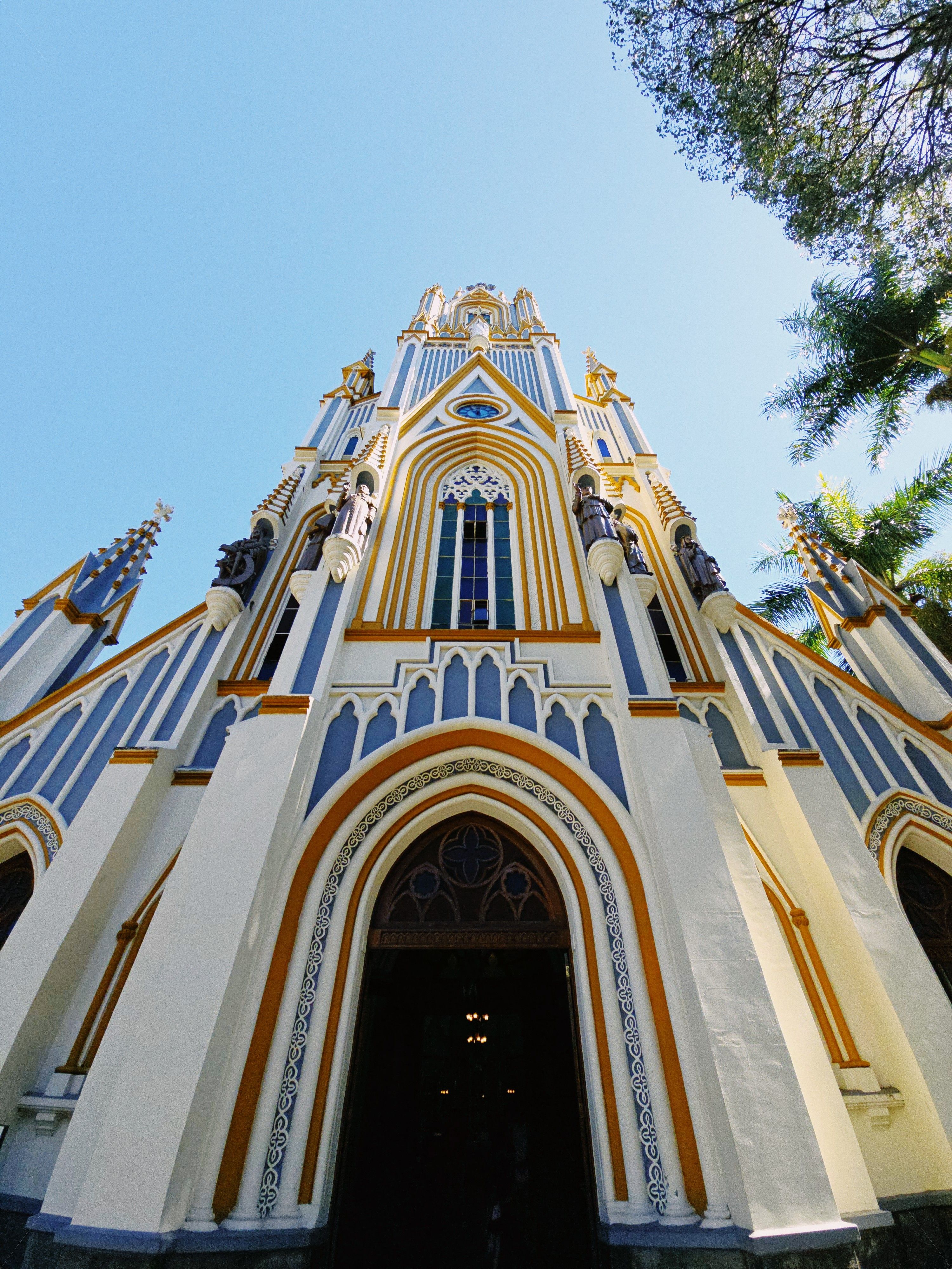 A tall white church with blue and yellow trim · Free Stock Photo