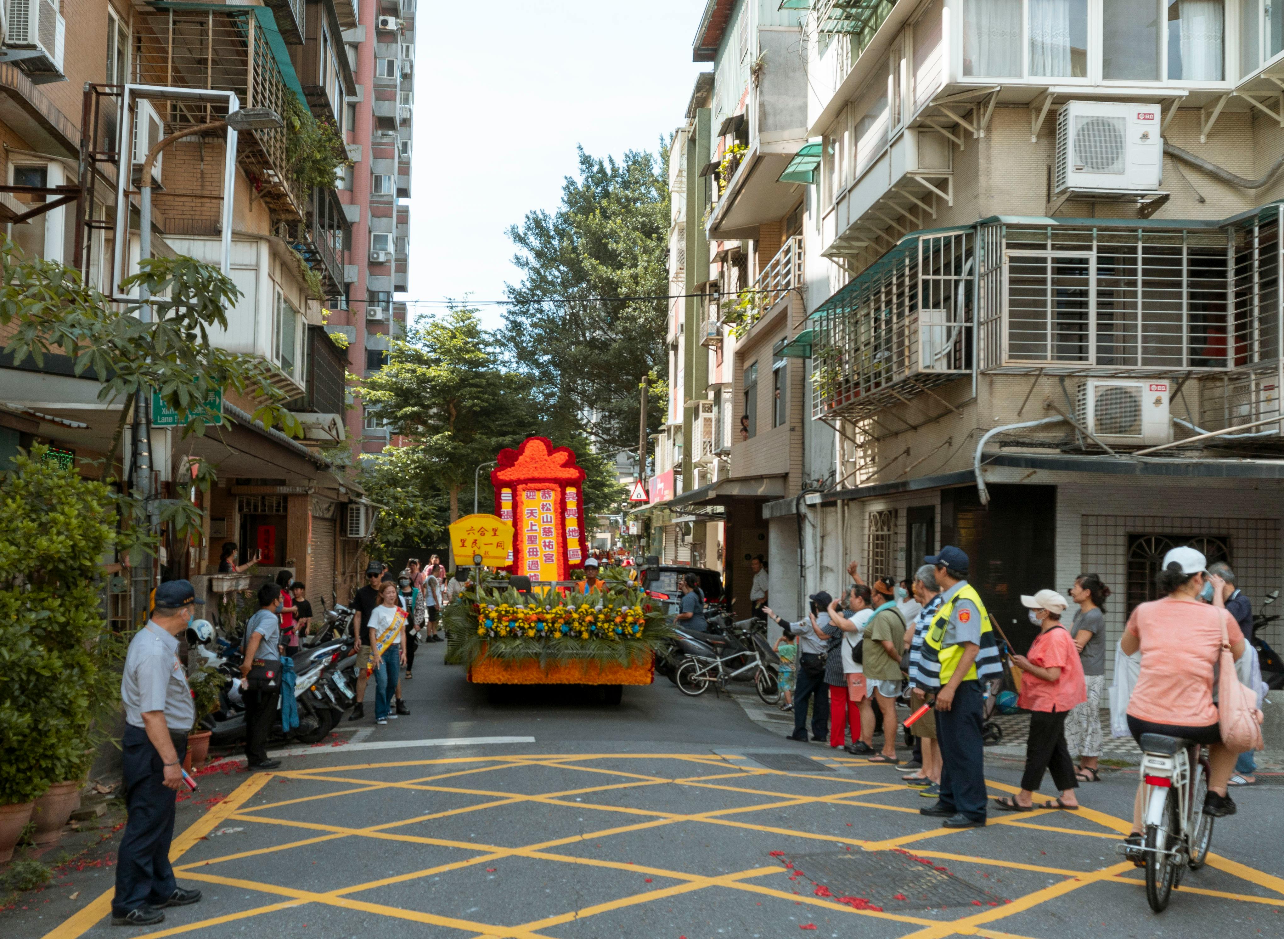 Pedestrians Looking at a Platform with Flowers on a Street at a Parade ...