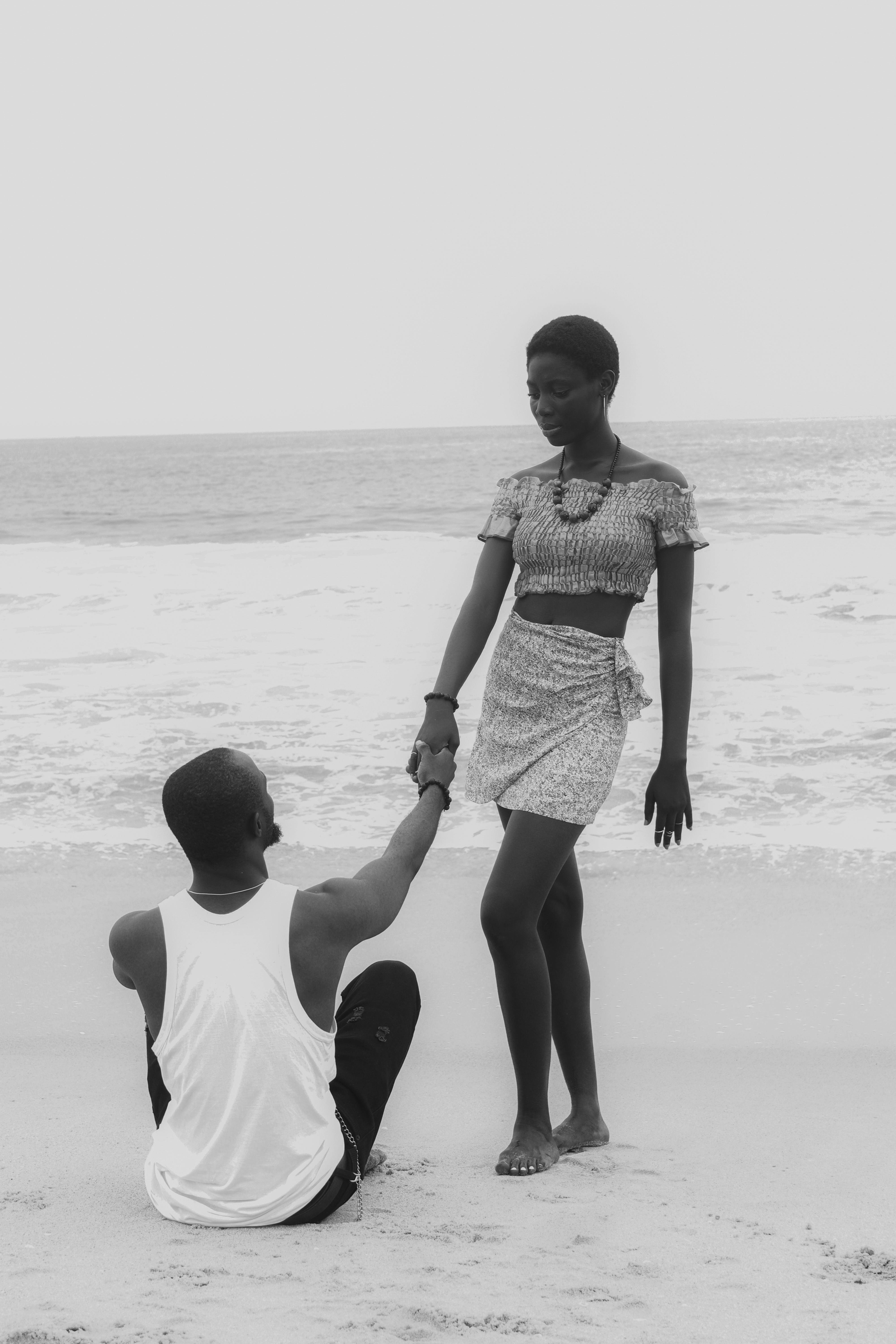 Woman Standing over Man Sitting on Beach · Free Stock Photo