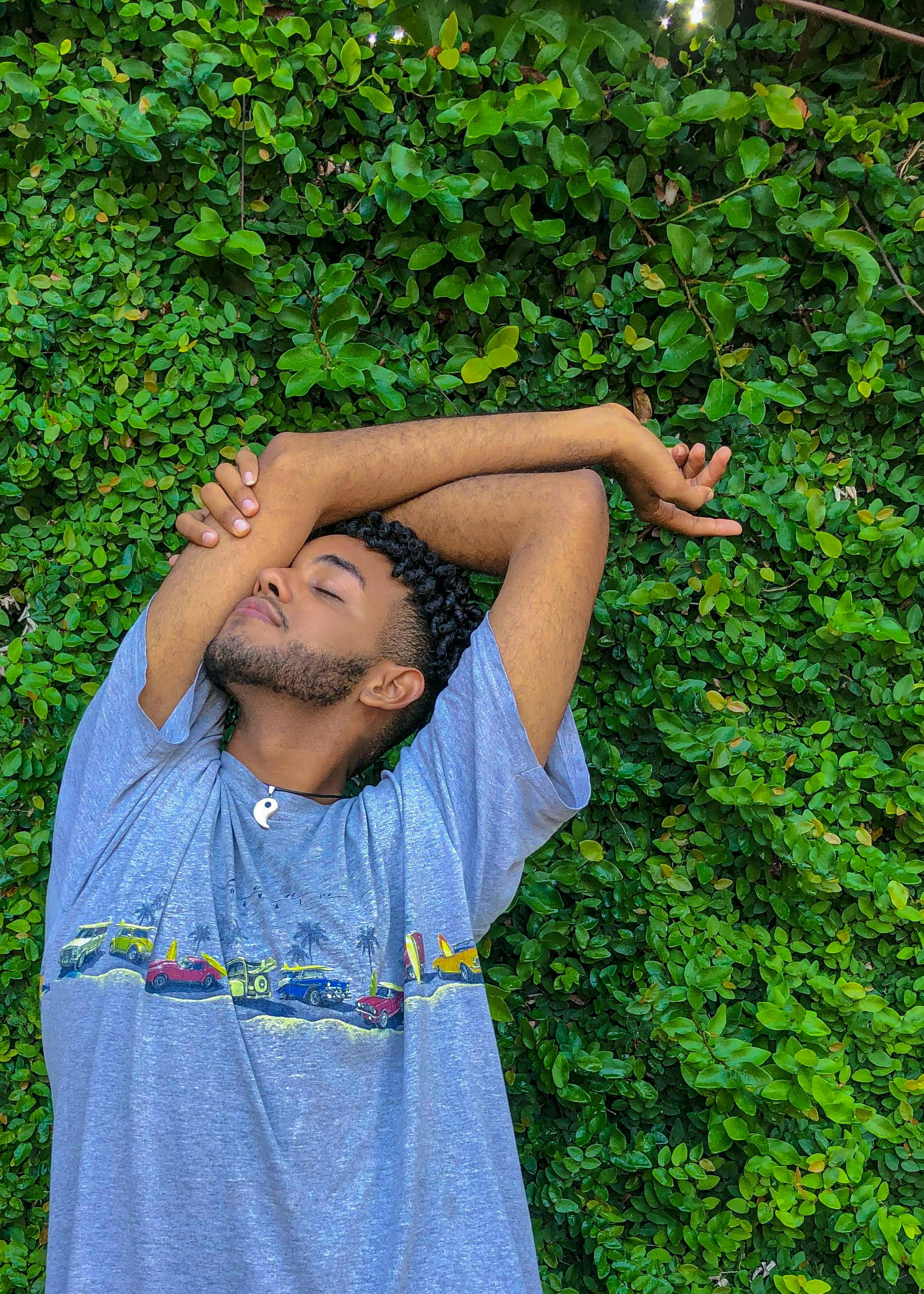 Man in T-shirt Standing with Arms Raised and Eyes Closed · Free Stock Photo