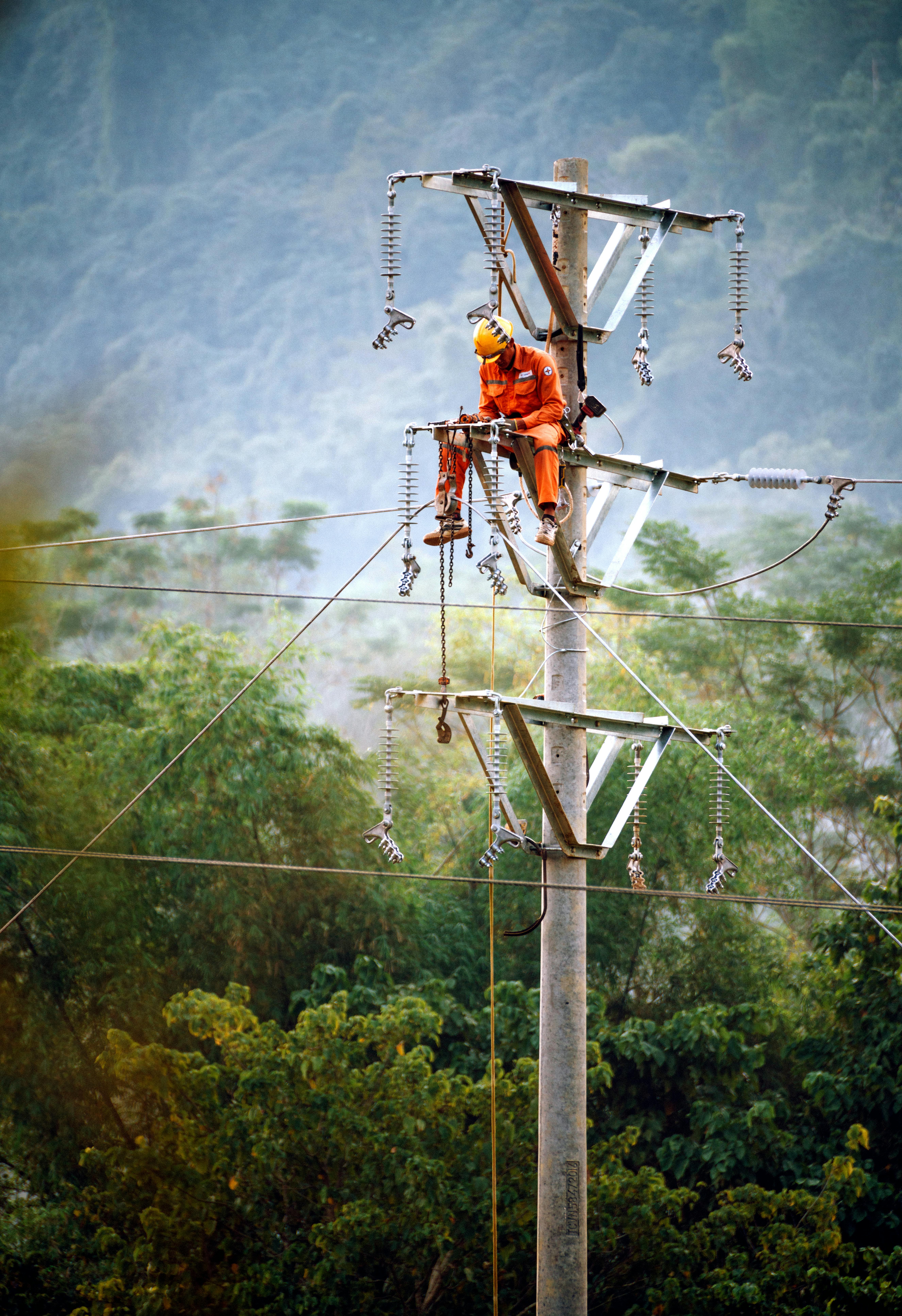 Sitting on Transmission Tower Man Fixing Electric Cables · Free Stock Photo