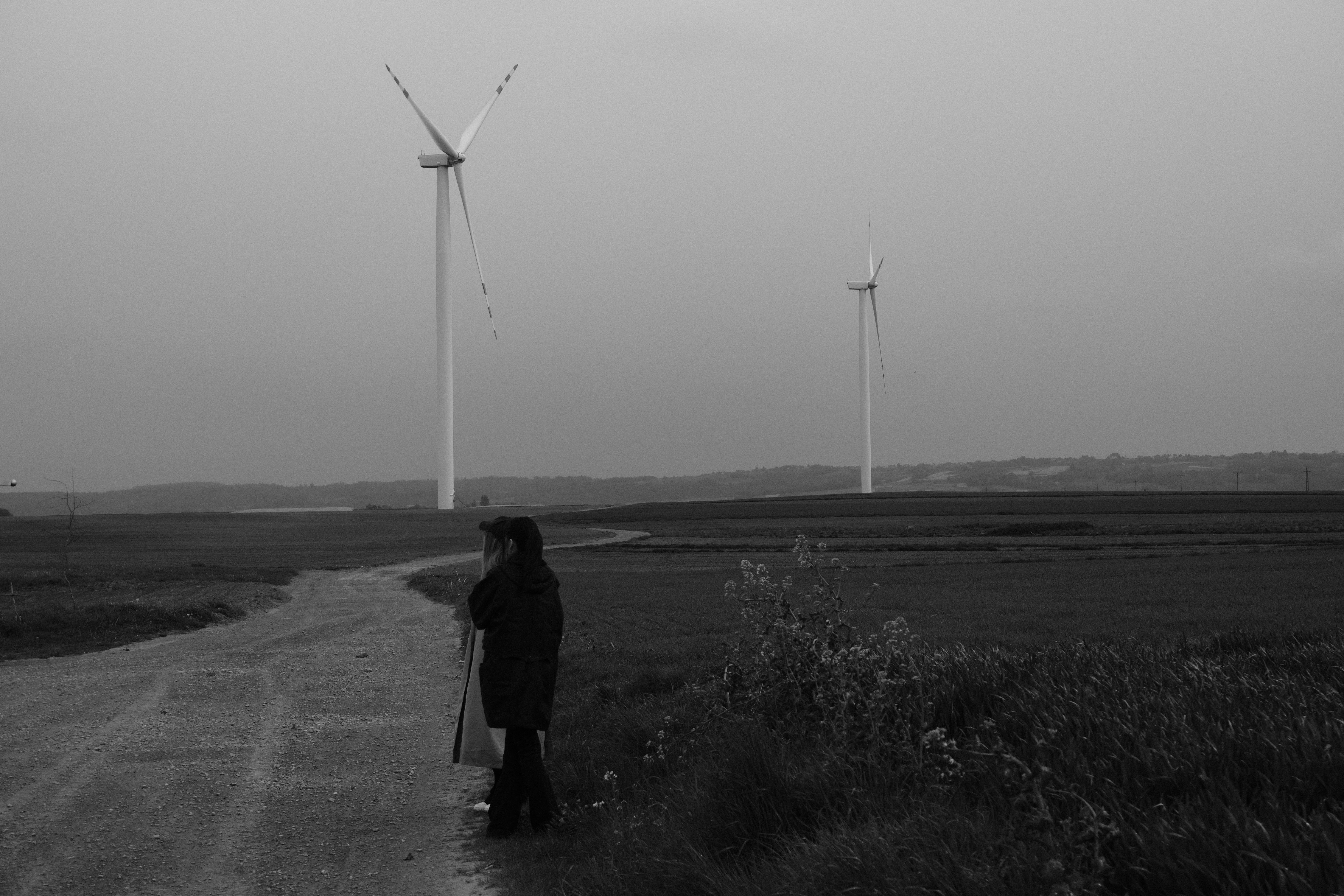 Black and White Photo of People Standing on a Field with Wind Turbines ...