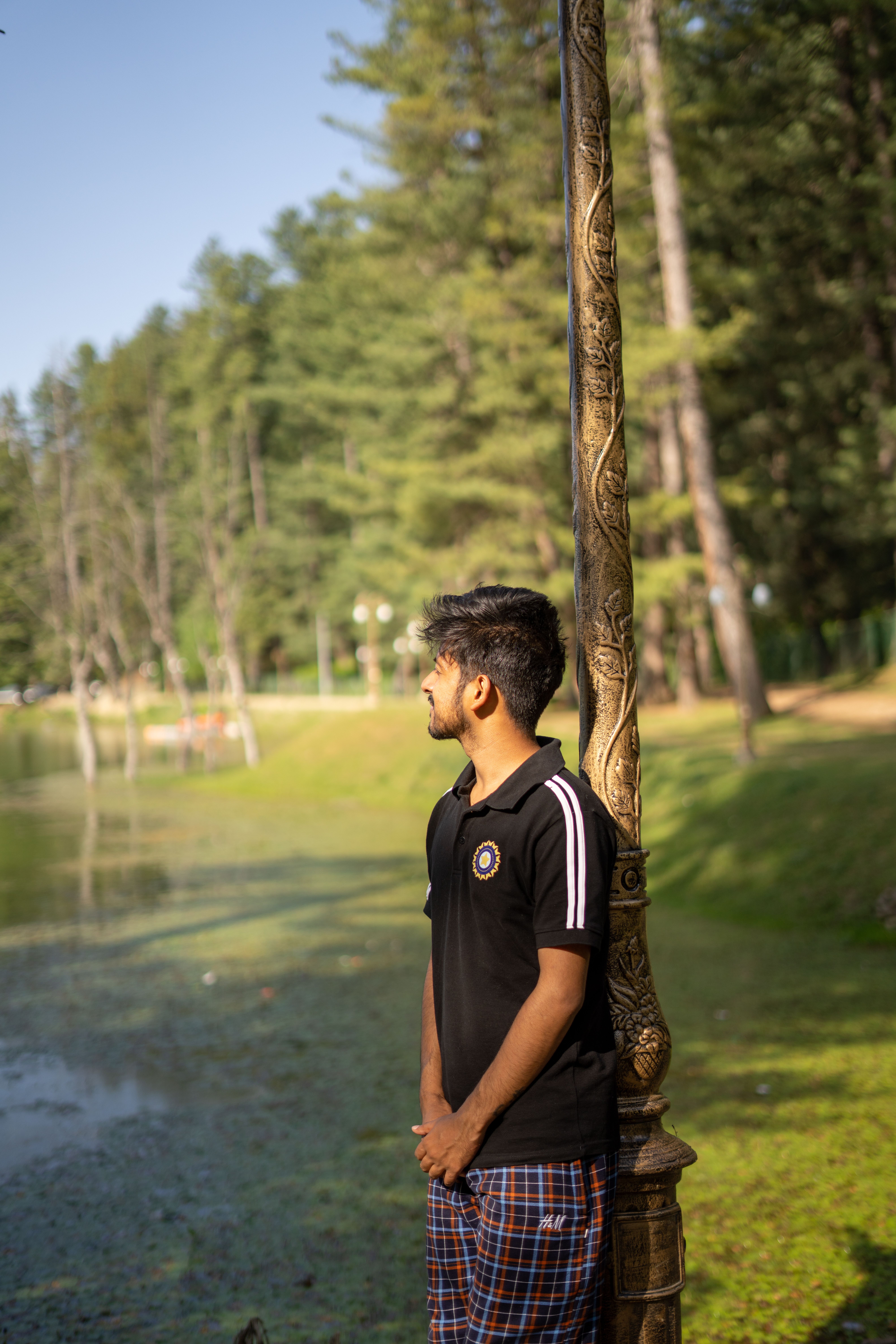 Man Leaning Against Lamppost by the Lake · Free Stock Photo