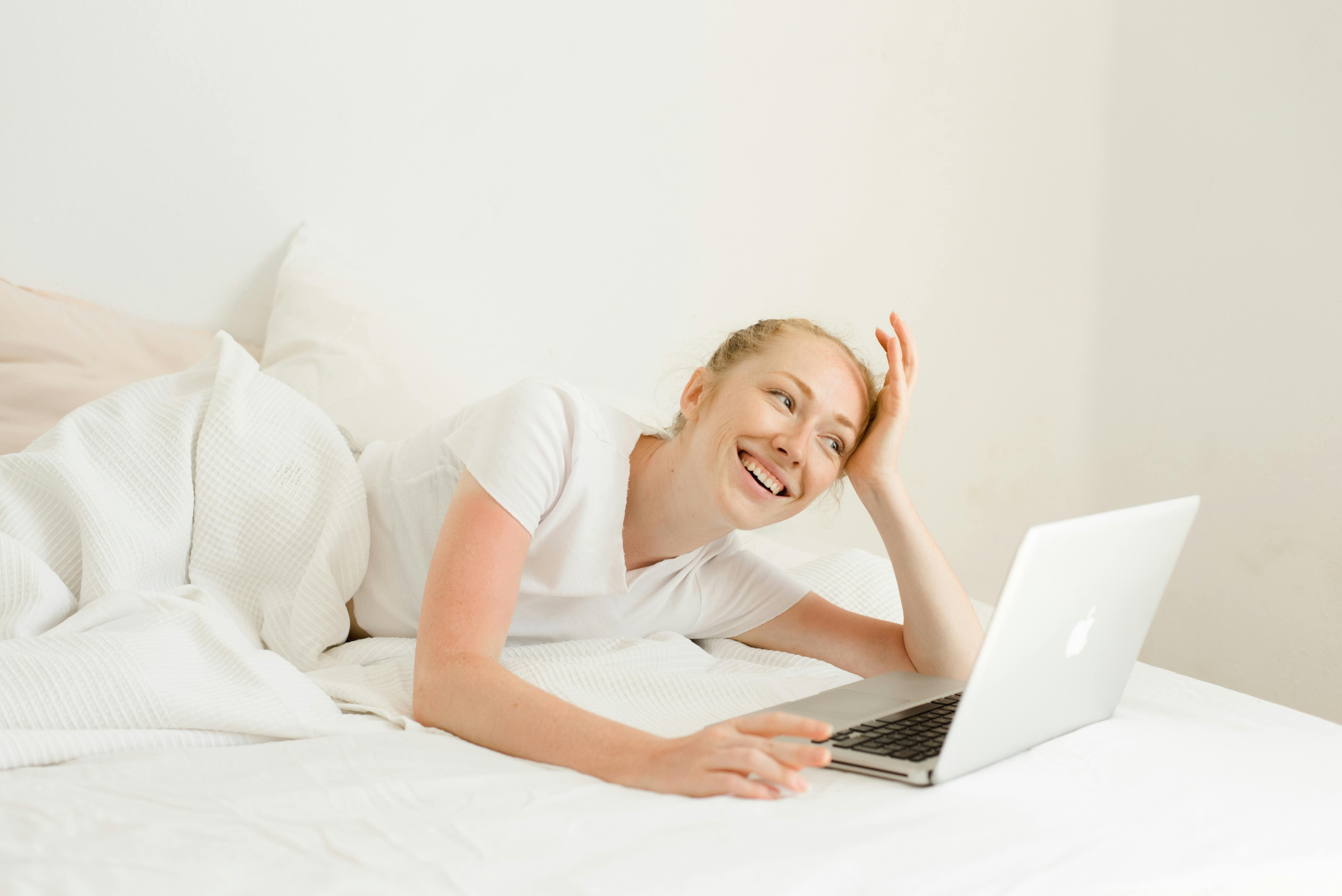 Smiling Woman Lying Down with Laptop in Bed · Free Stock Photo