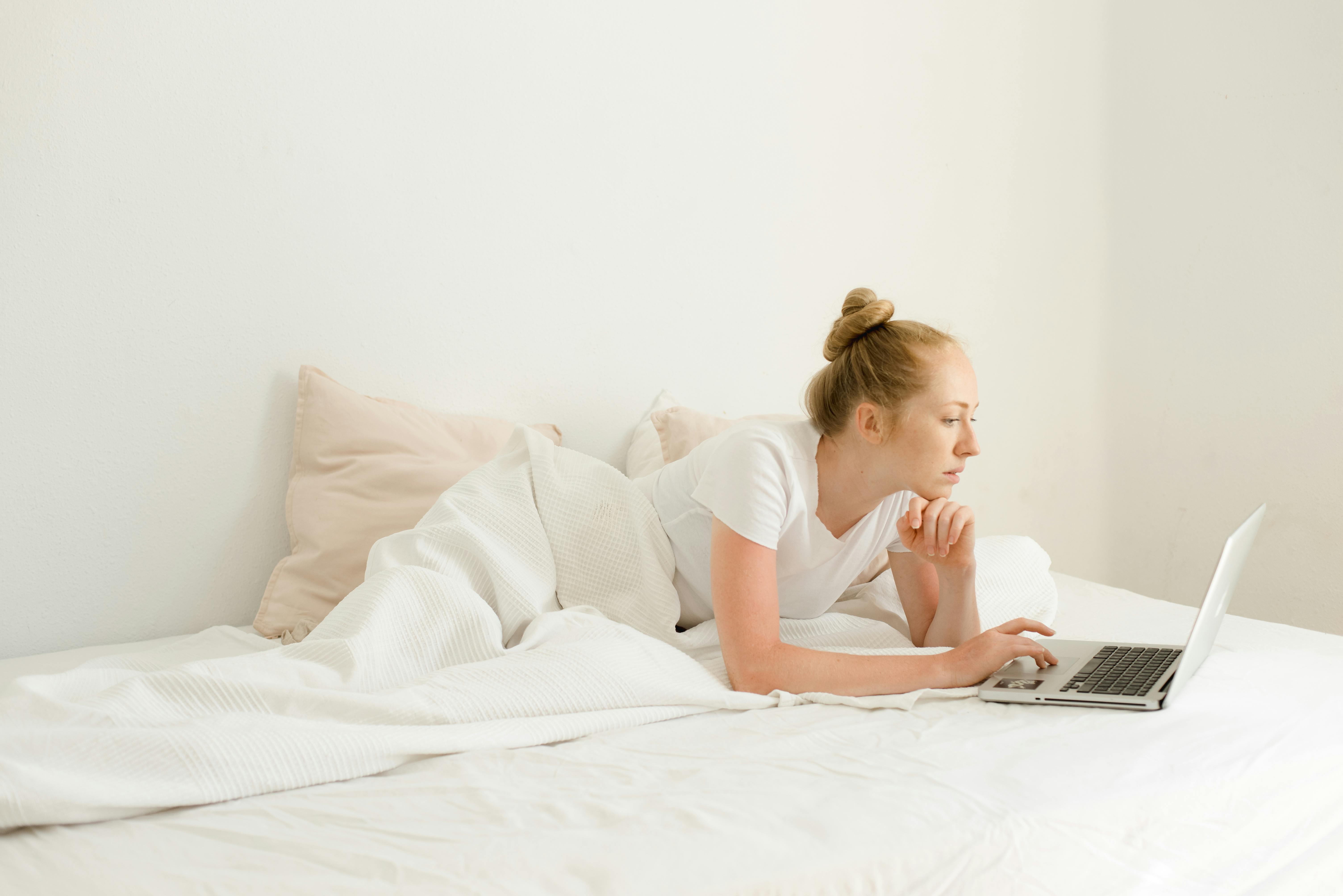 Woman Lying Down and Using Laptop on Bed · Free Stock Photo
