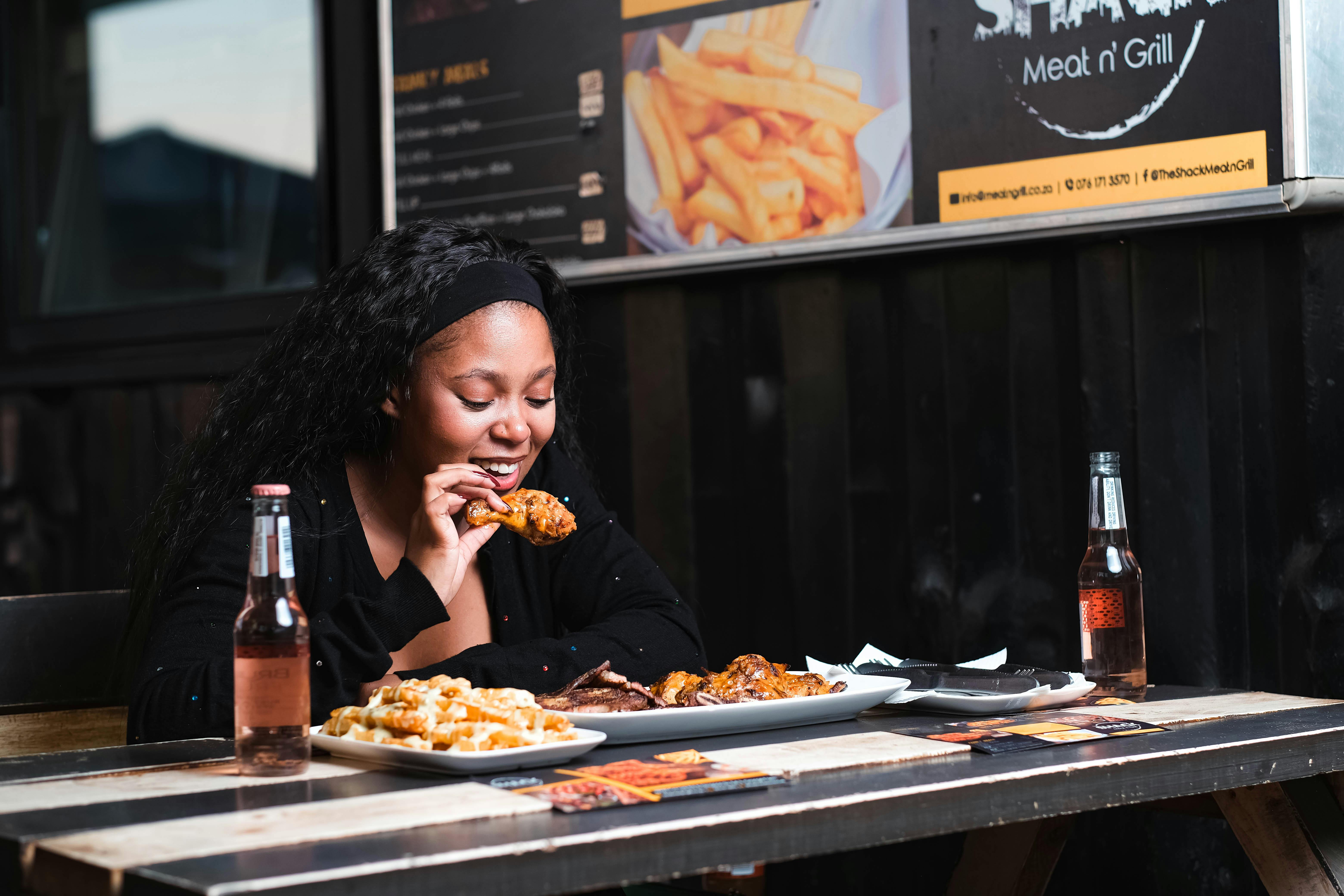 A Woman Eating Chicken at the Restaurant · Free Stock Photo
