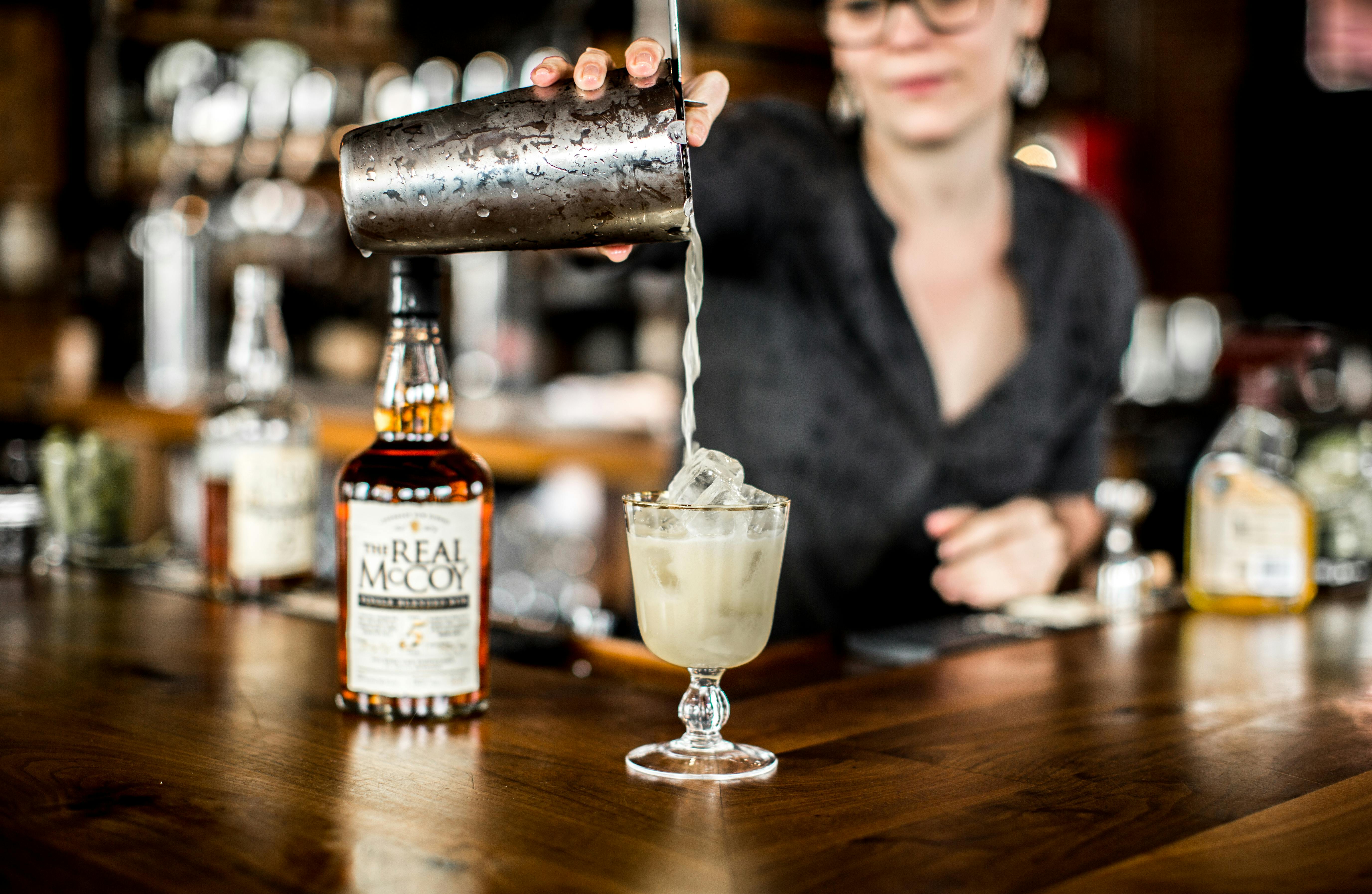 A bartender pouring a drink into a glass · Free Stock Photo