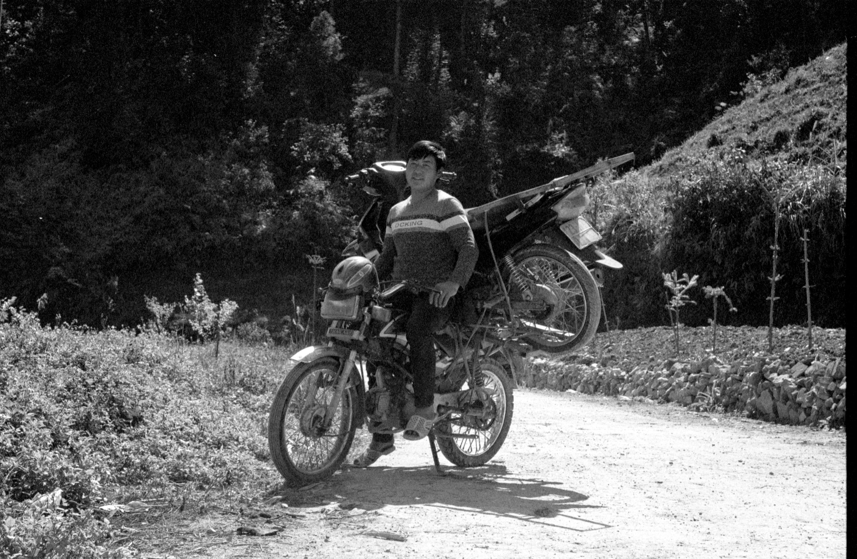 Man Sitting on Motorbike Carrying Motorbike on Dirt Road · Free Stock Photo